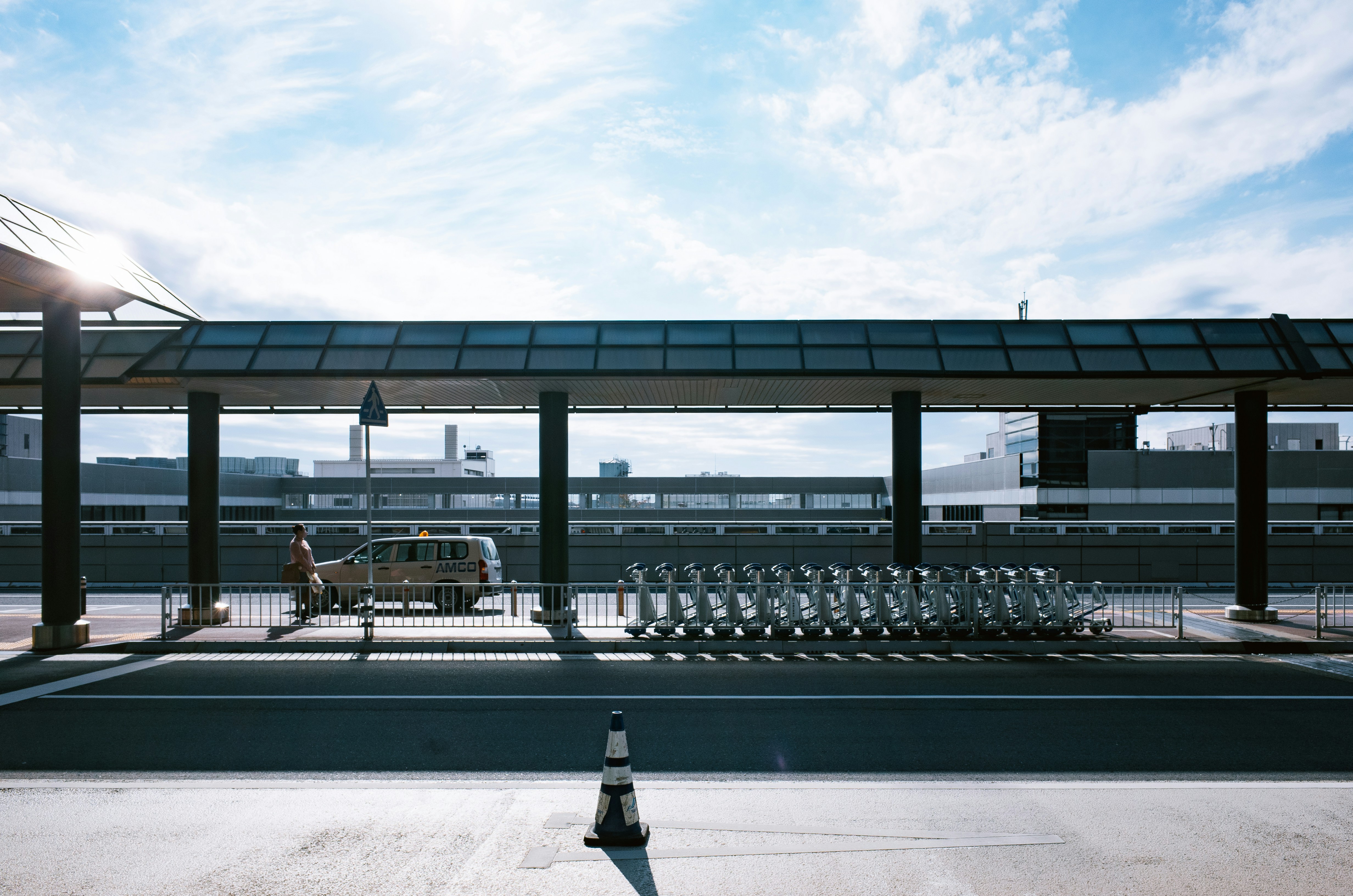 Line of wheels and a lone passenger under a glass canopy