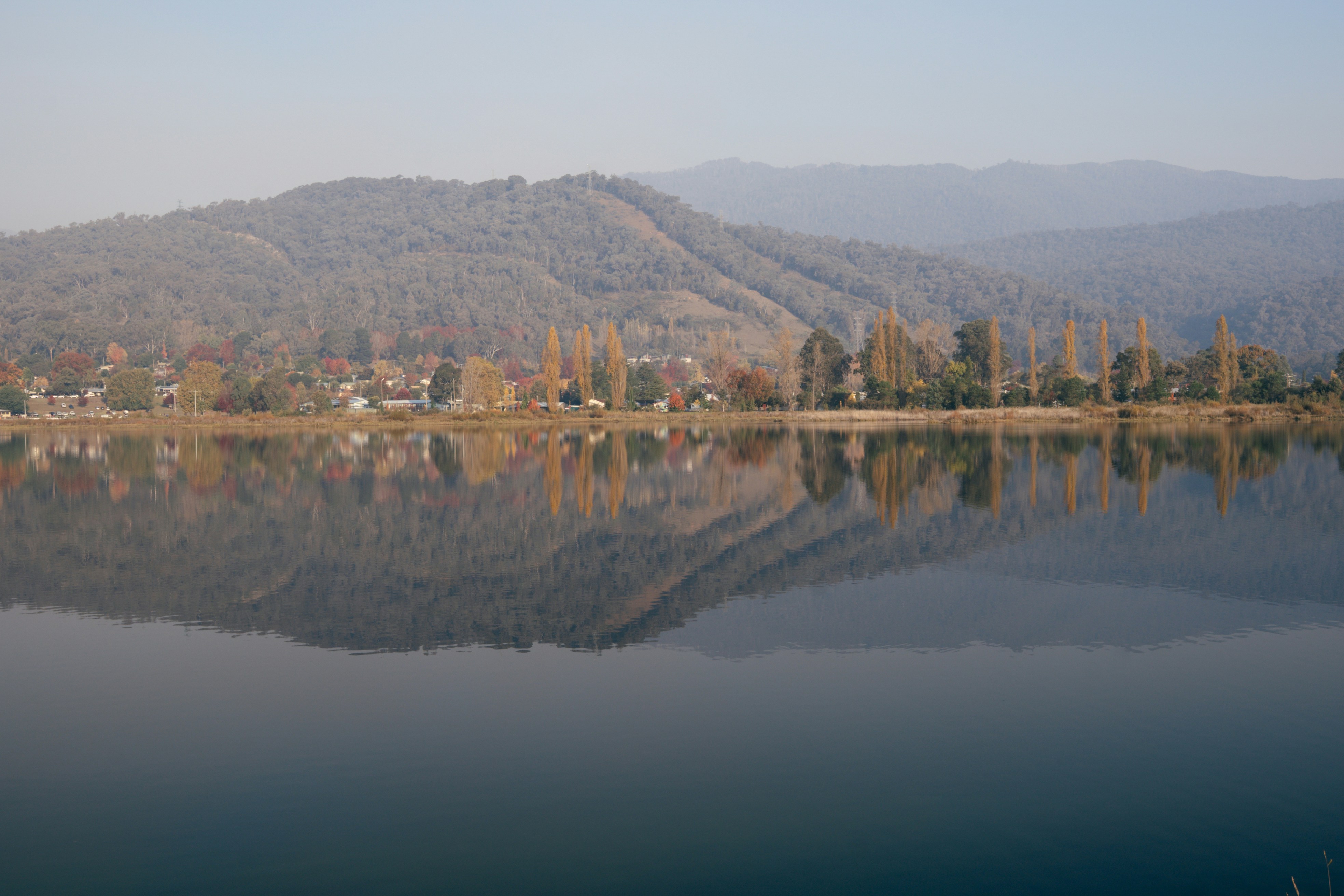Serene lakeside village mirrored by autumn hills