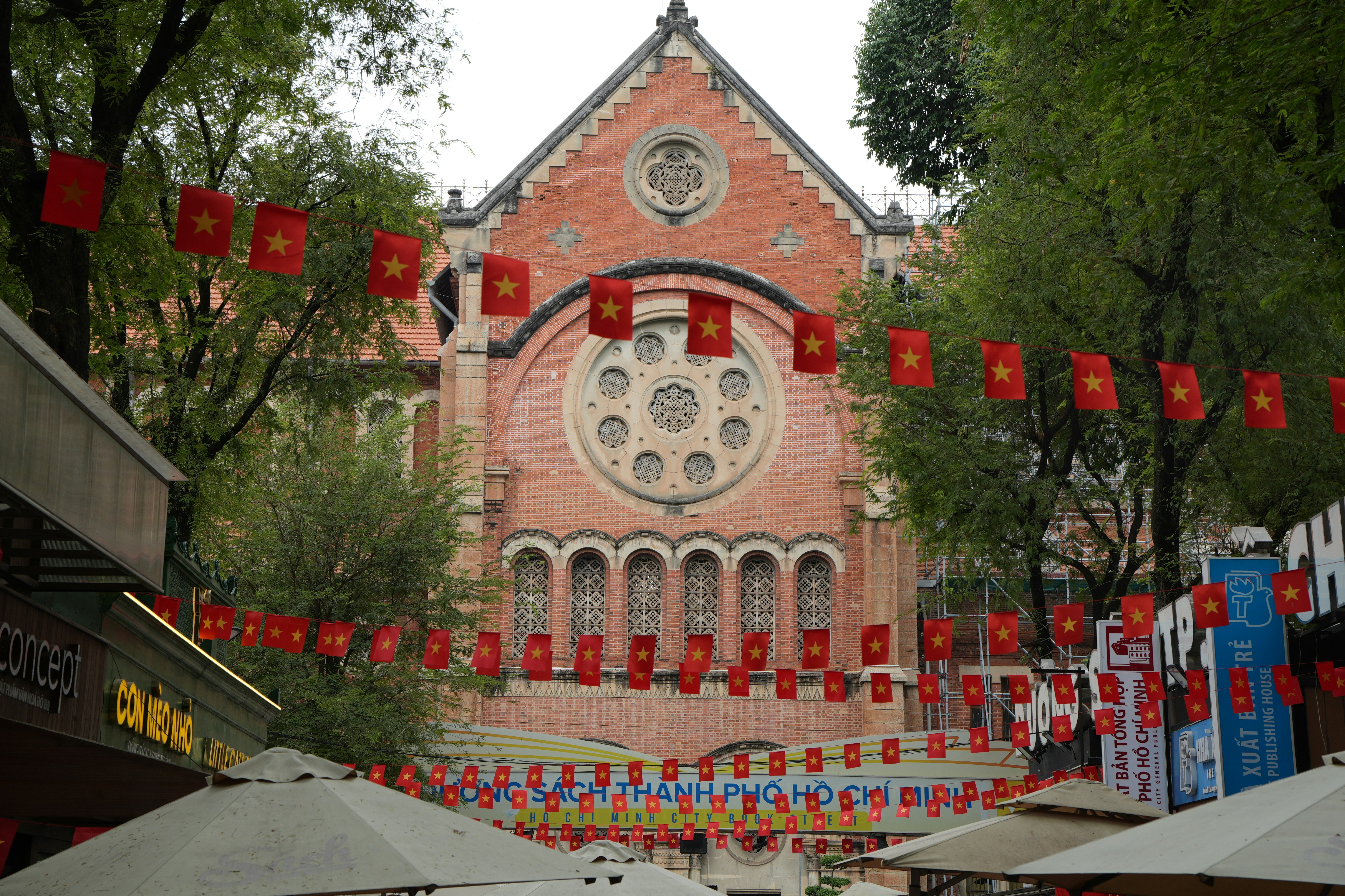 Pink cathedral adorned with red flags in a bustling street.