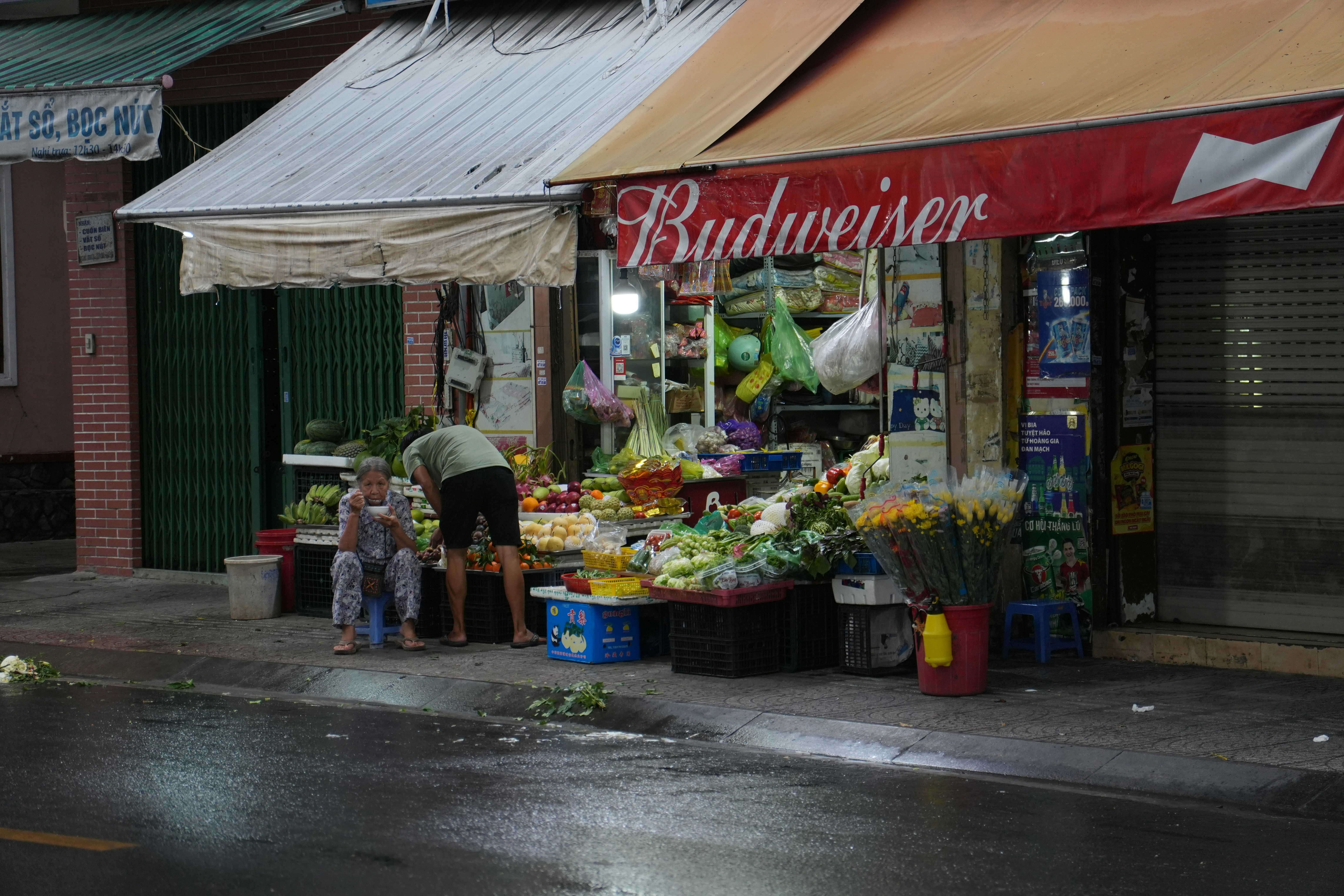 Market Stall Beneath a Red Budweiser Awning on a Rainy Street
