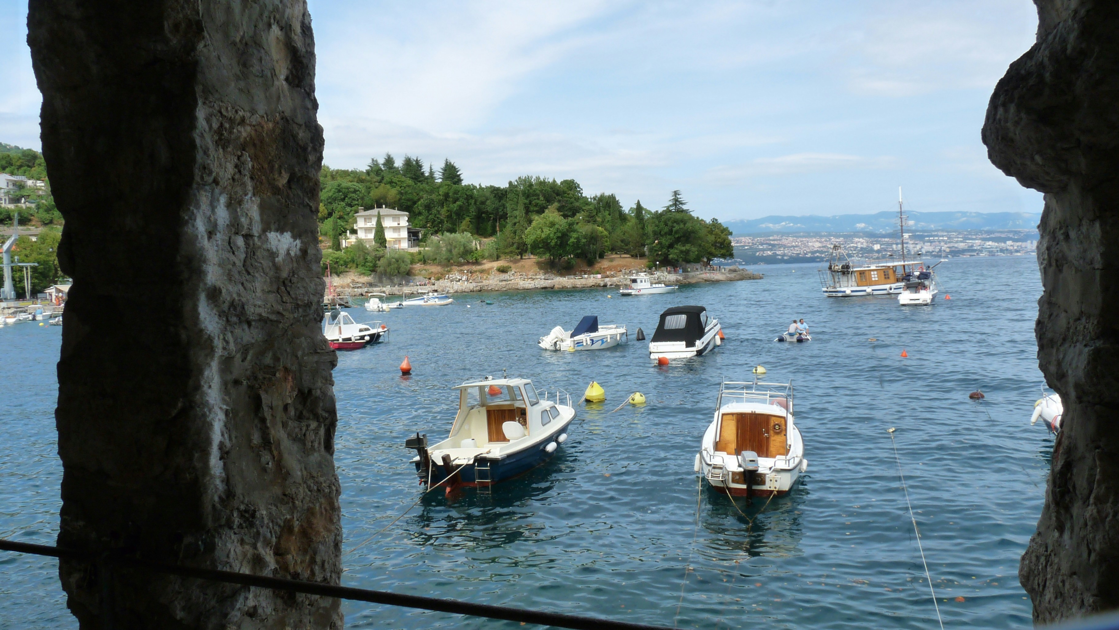 Sunlit Boats Nestle in a Coastal Window Framed by Stone Cliffs