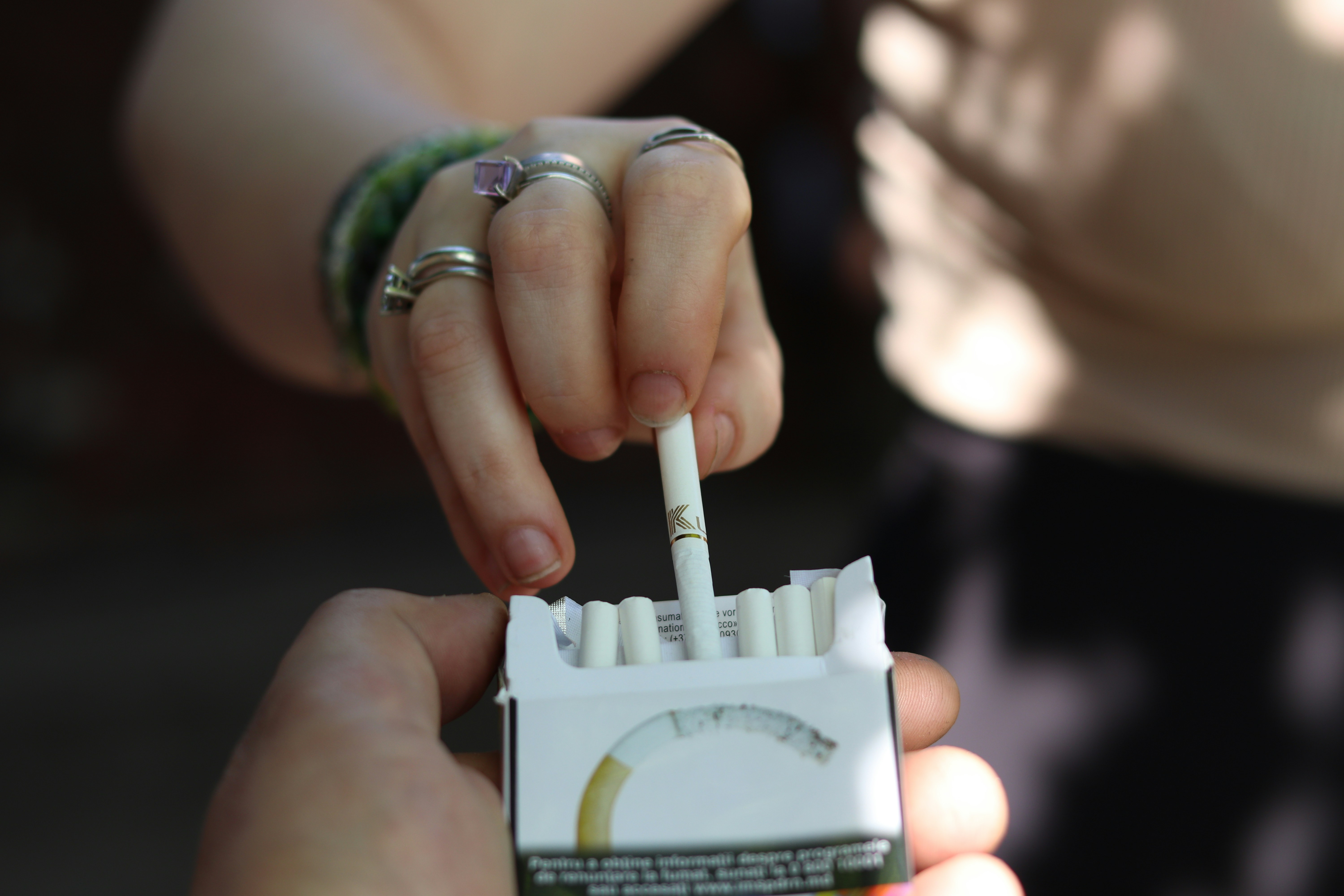 Close-up of a hand lighting a cigarette from a pack held in the other hand