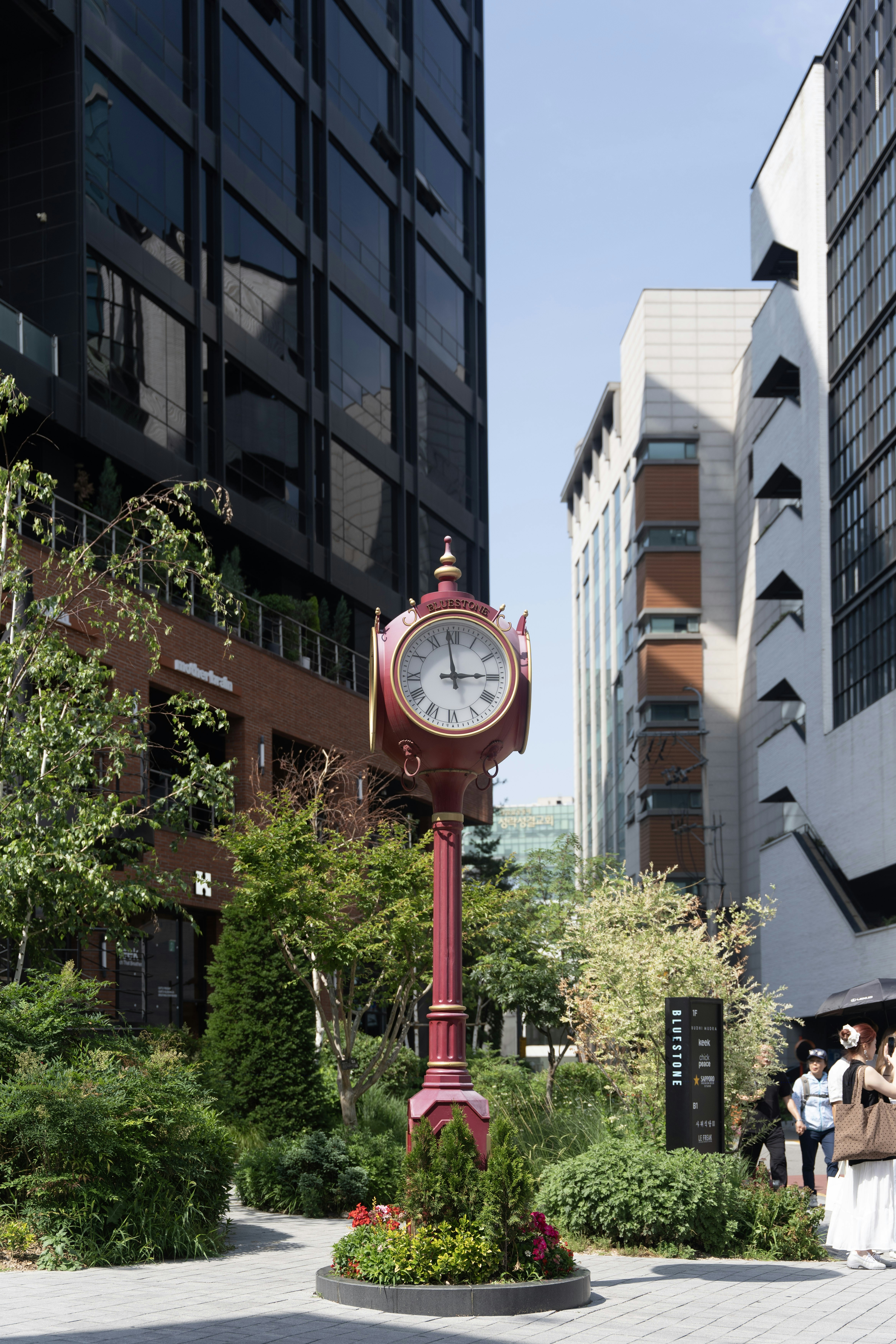Urban Timekeeper: A Crimson Clock Stands Between Glass Towers