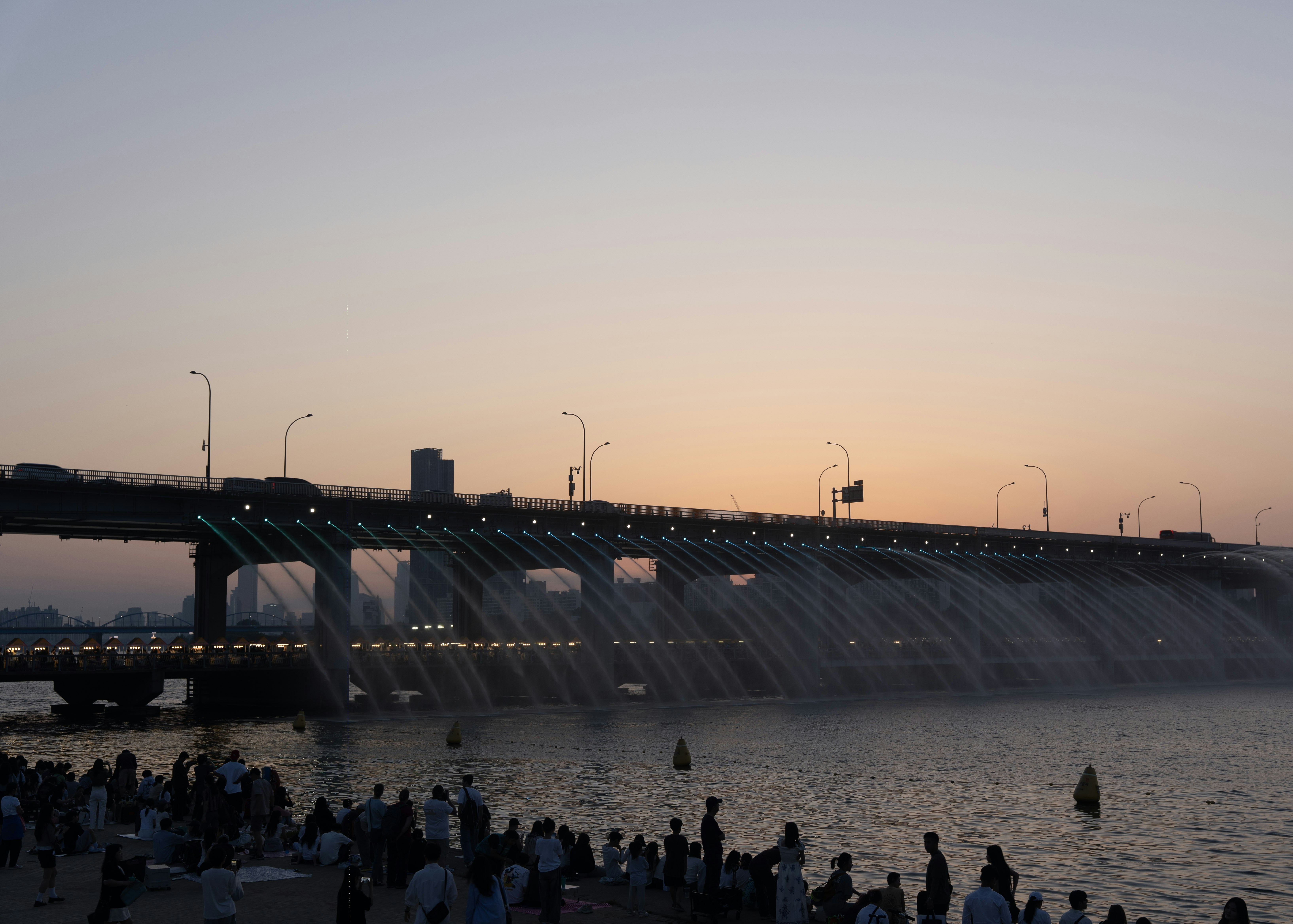 Sunset Over the Spillway Bridge: silhouettes and crowds along the riverbank