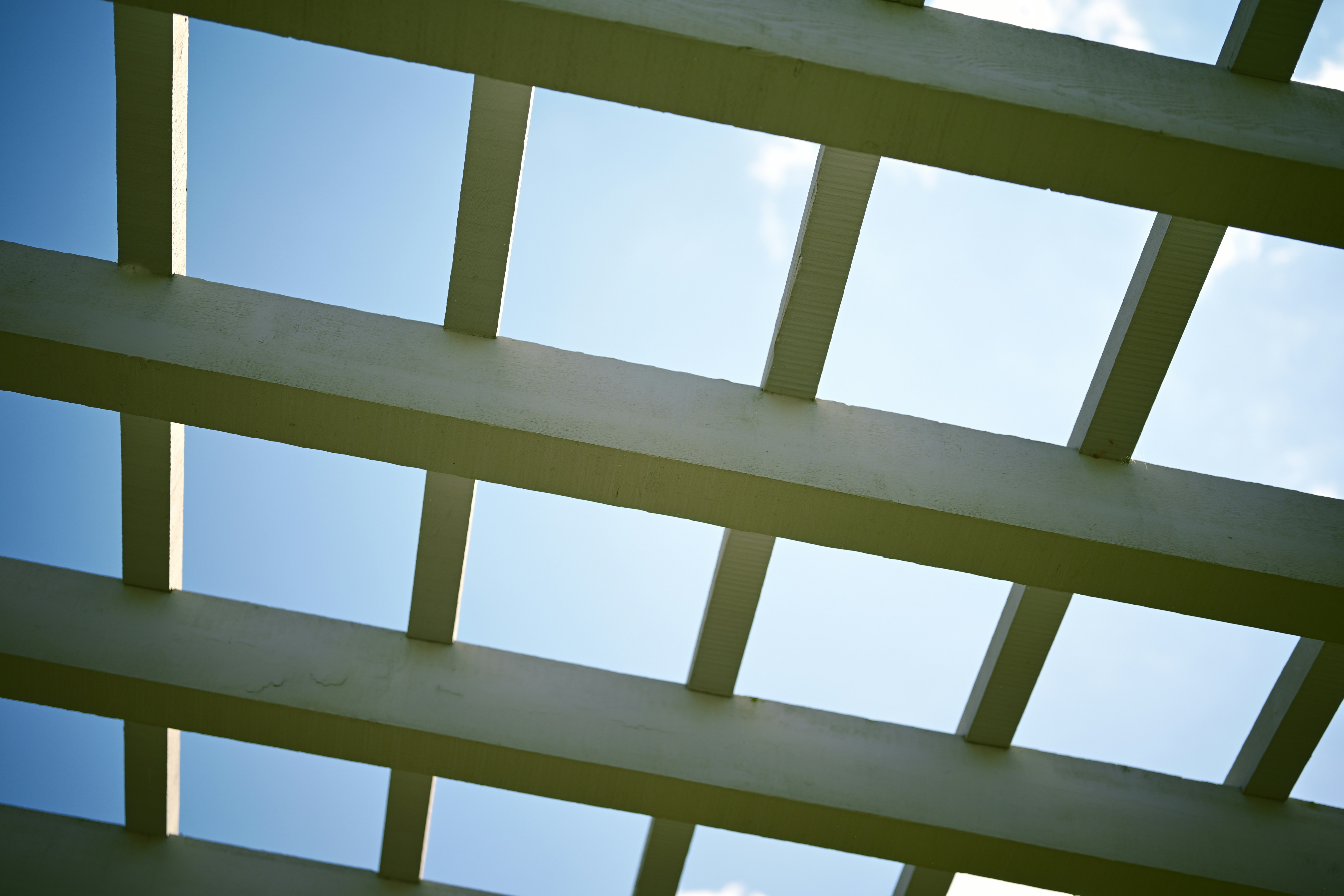 A wooden trellis structure against a clear blue sky.