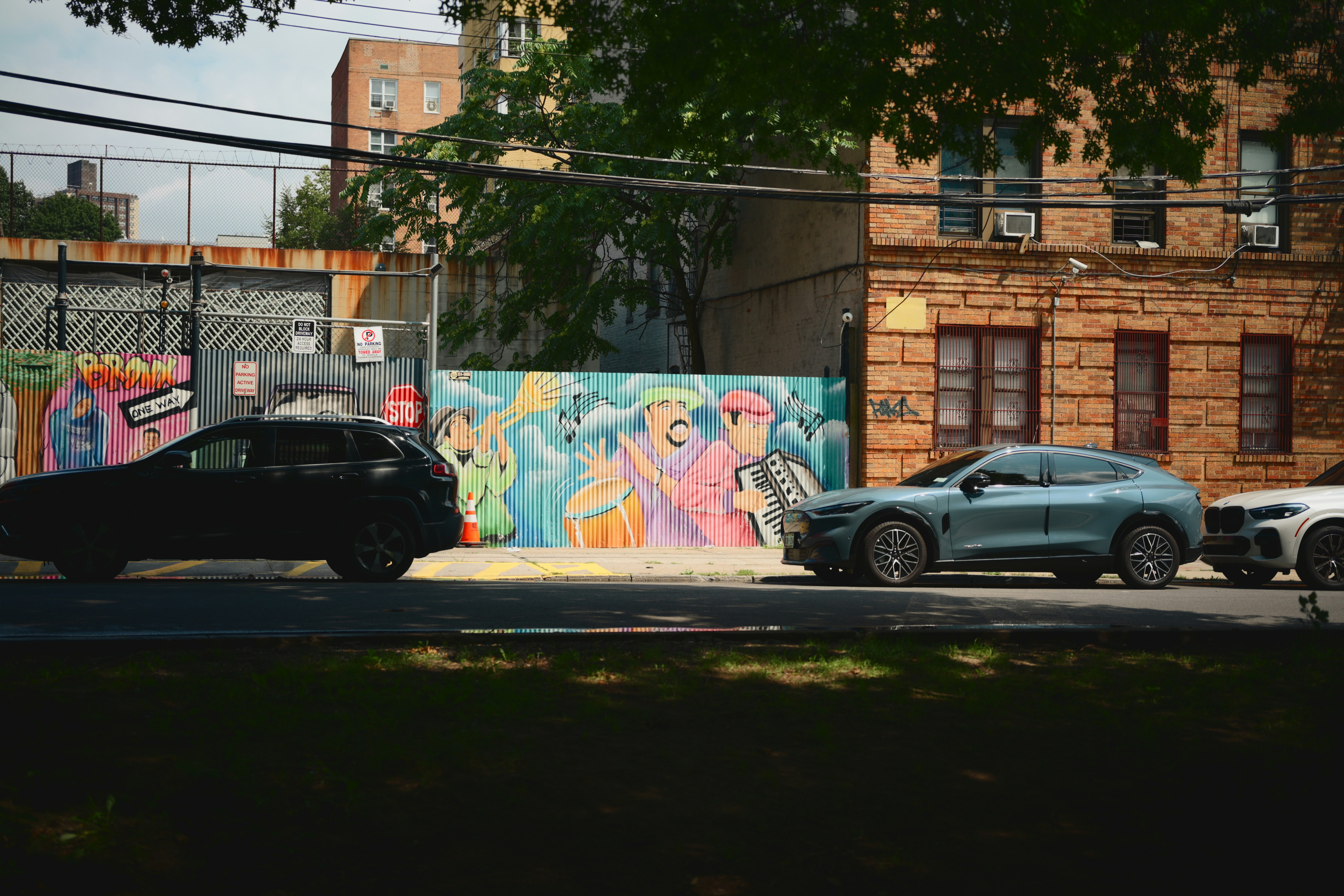 Chromatic Lane: Cars Pause Before a Muraled City Block