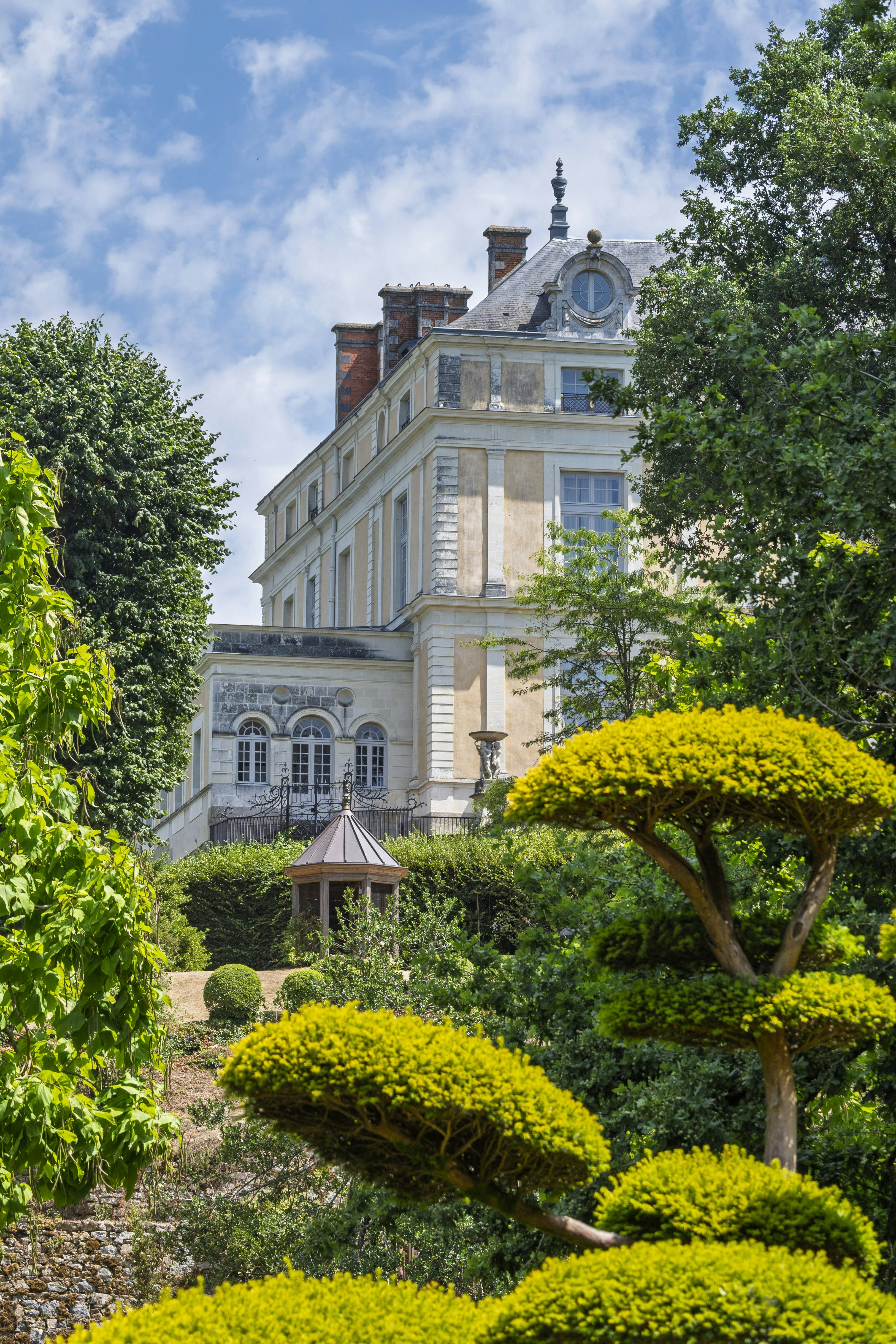 Sunlit Mansion Garden Framed by Sculpted Pines