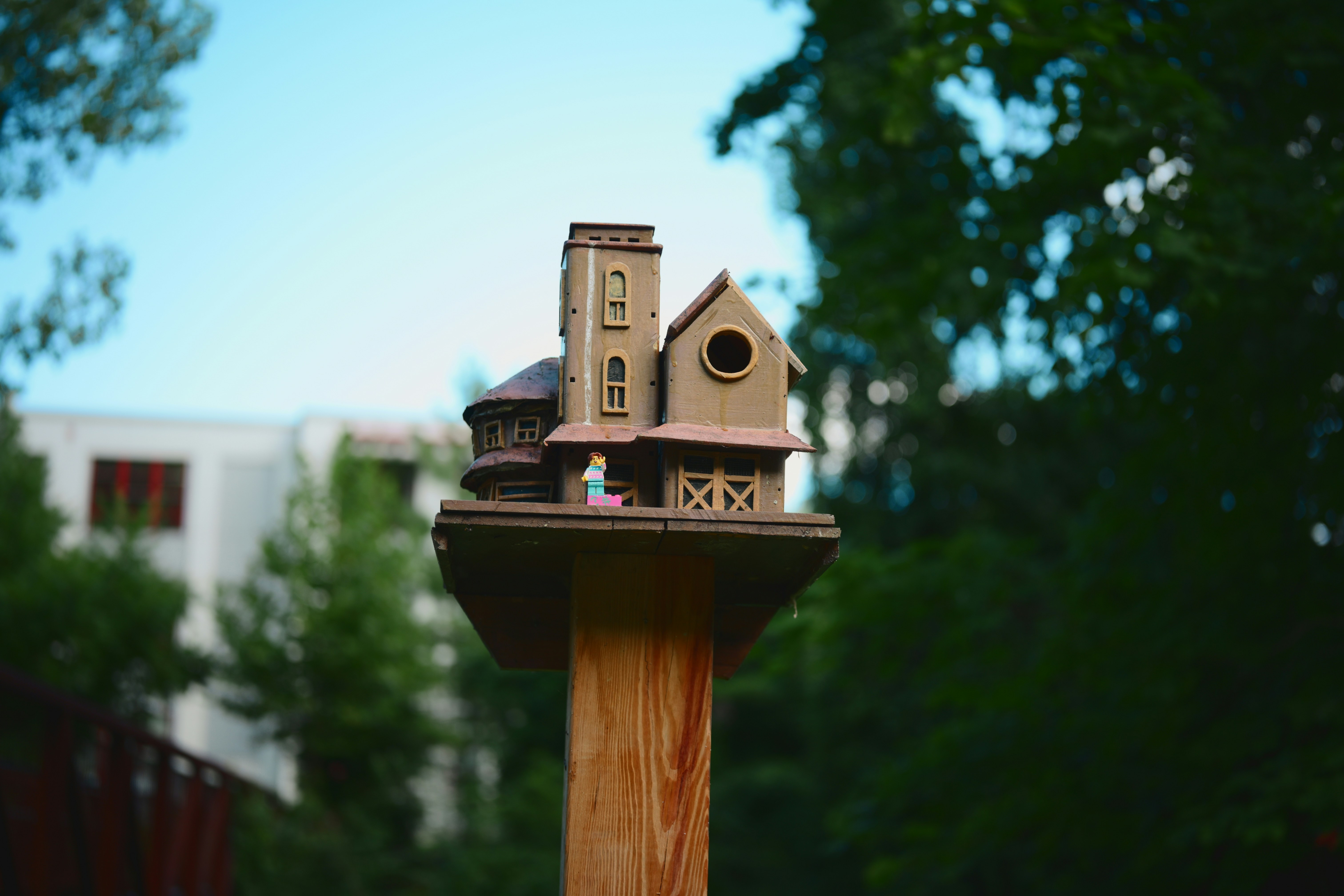A miniature wooden house on a pedestal amid a lush garden