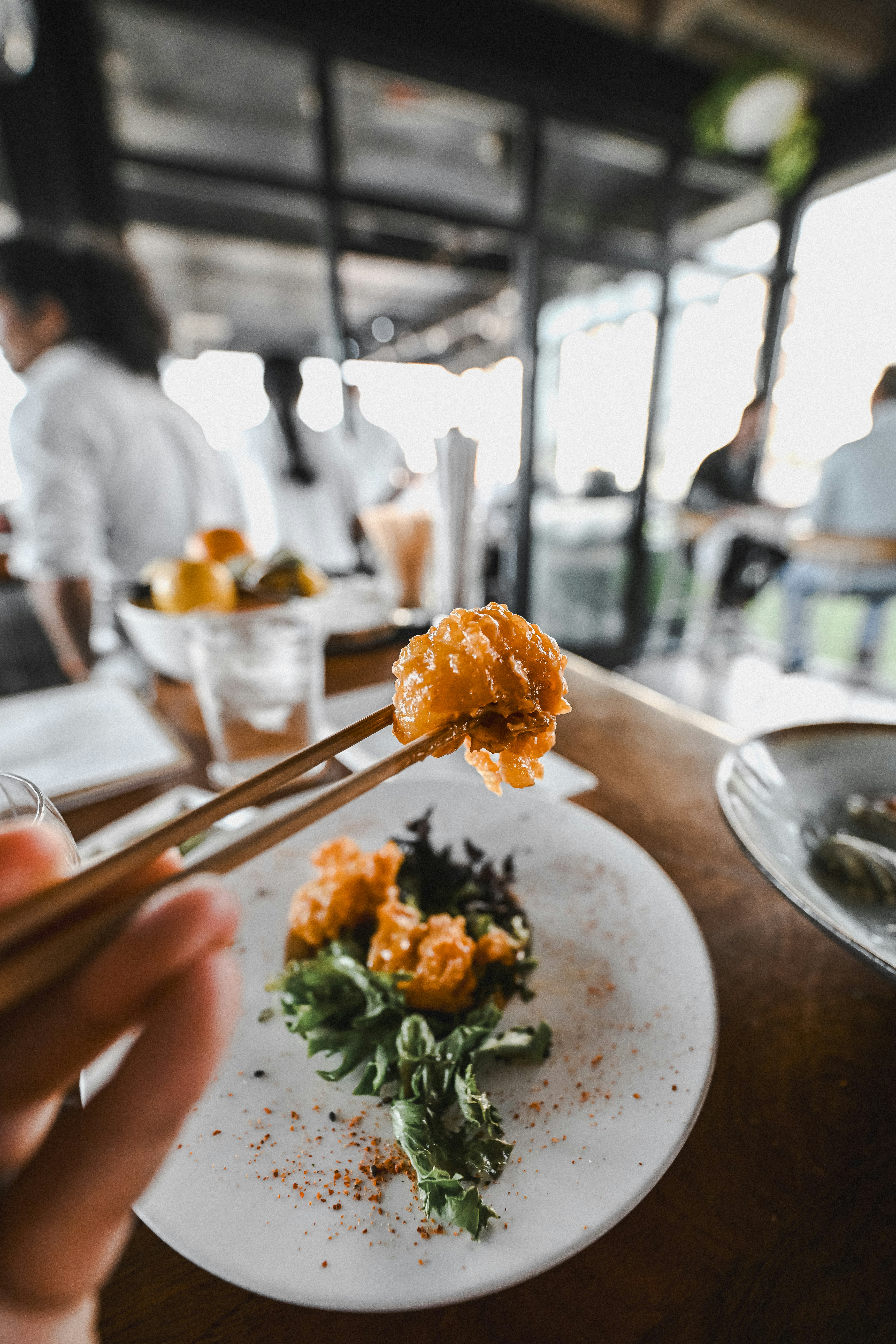 Chopsticks Lift Crispy Glow: A Delicate Bite Over a Garden Plate