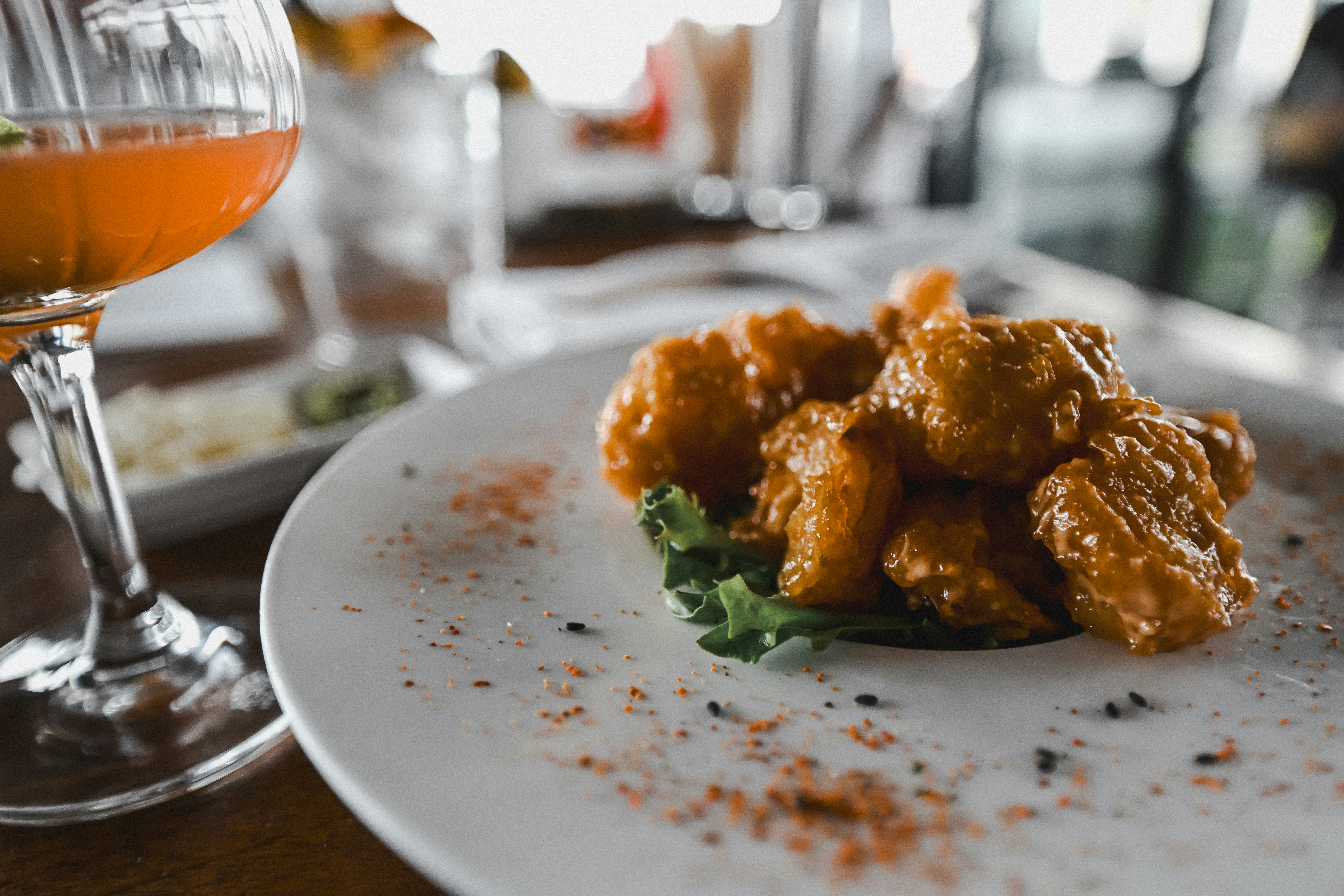 Crispy morsels on a plate, with a wineglass halo in the foreground
