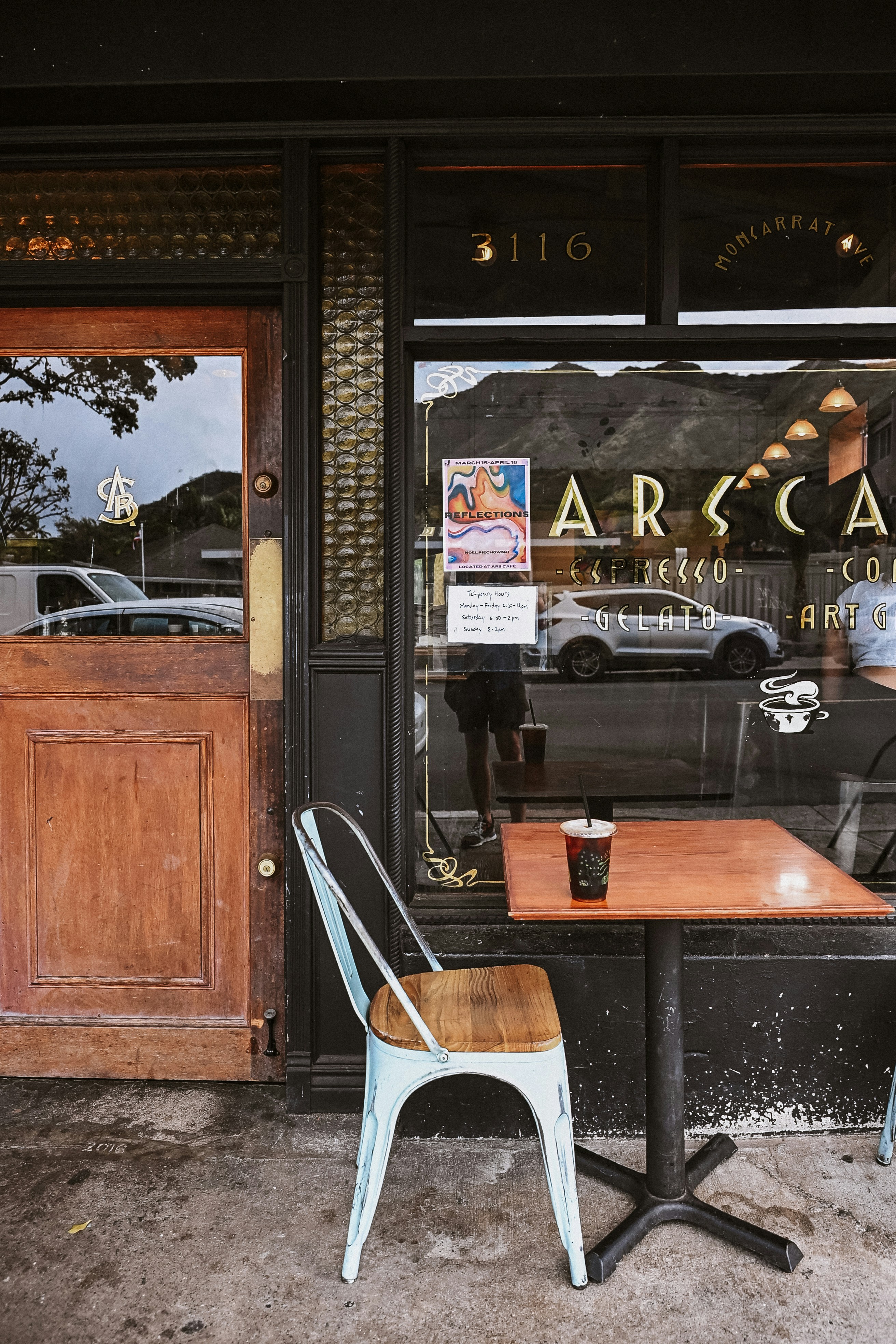 Exterior of a coffee shop with a table and drink.