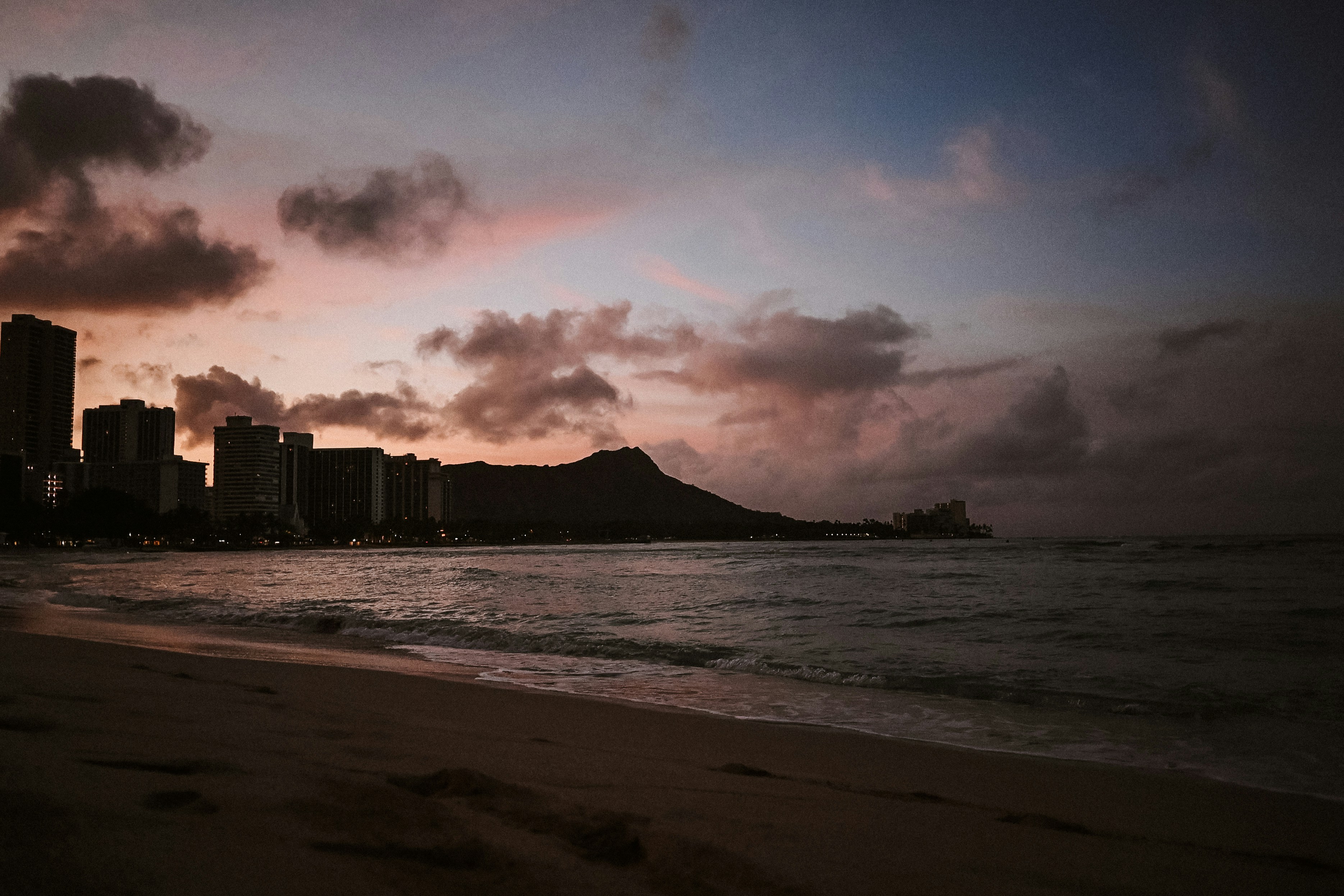 City skyline and diamond head at sunset from a beach.