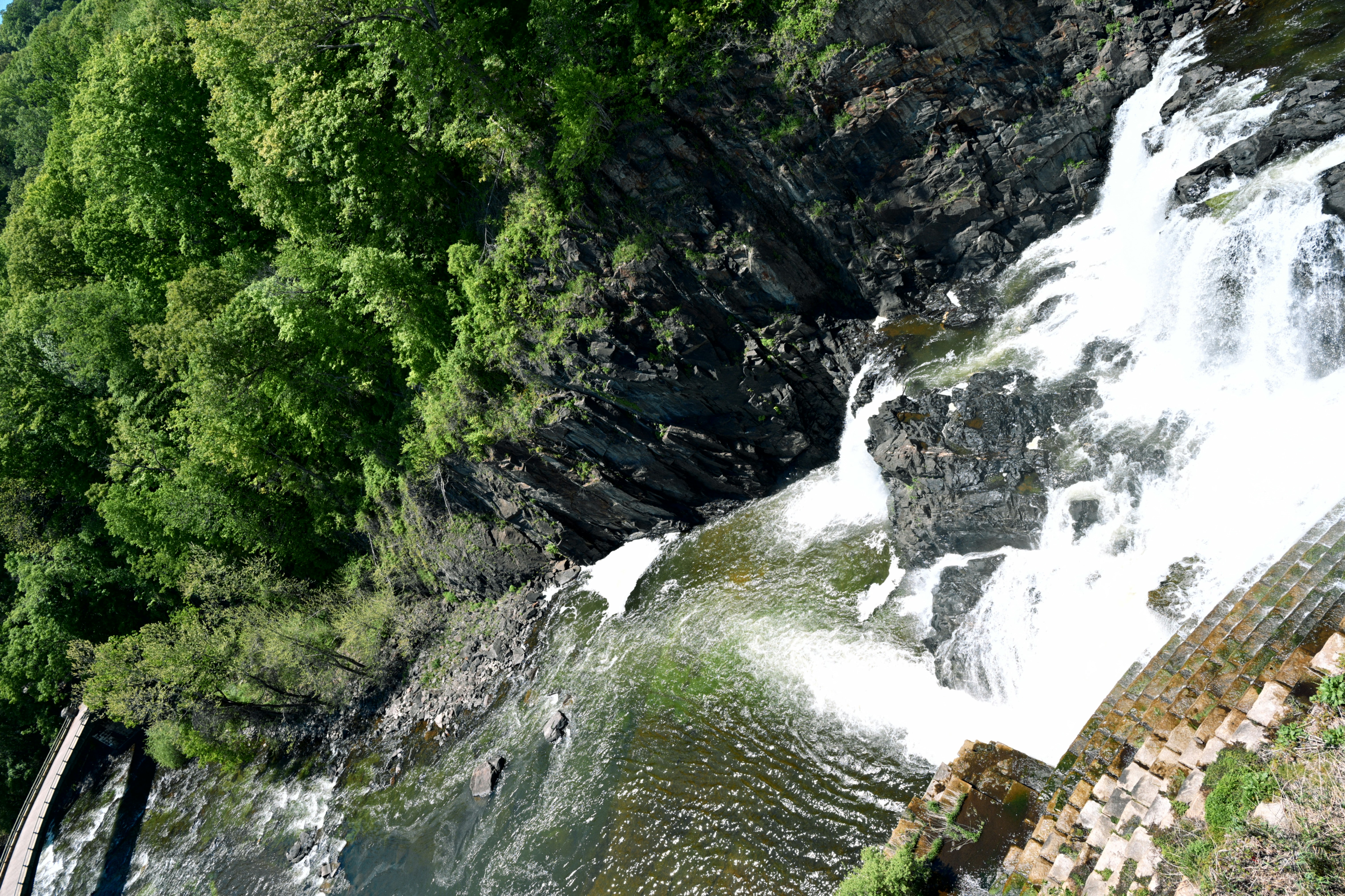 Waterfall cascading down rocky cliffs amidst lush green trees.