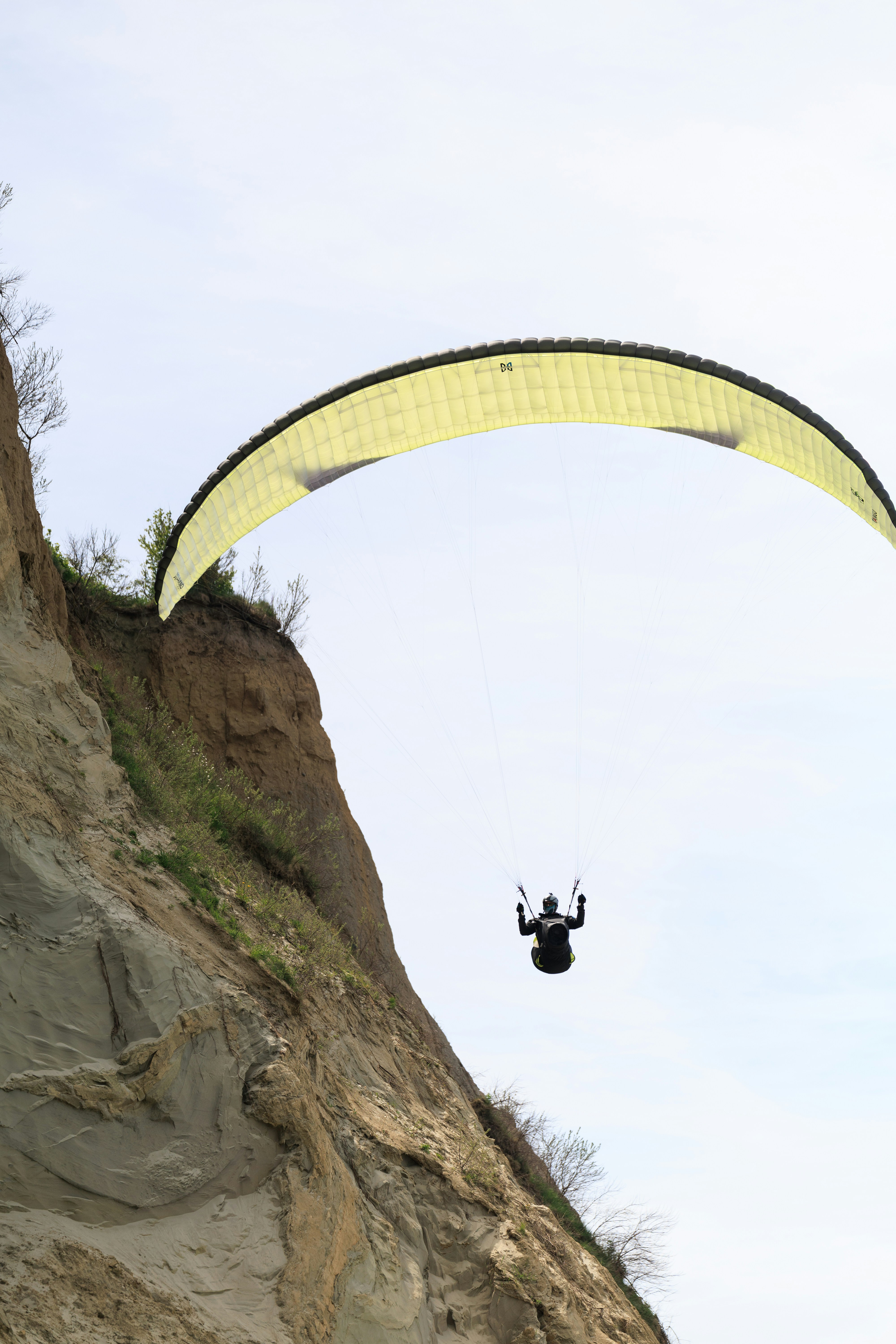 Skyward Glide: A Paraglider Rises from a rugged cliff