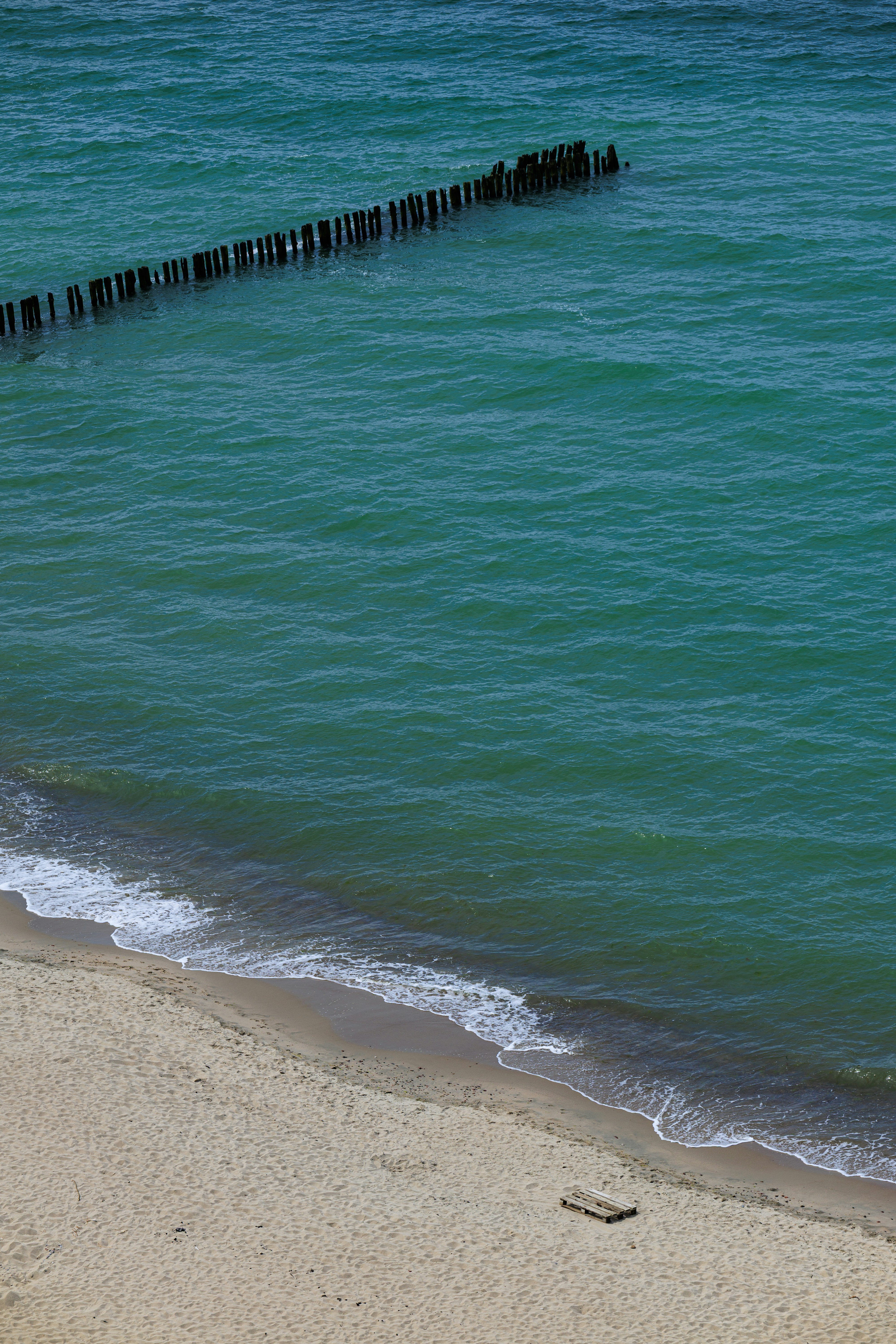 Secluded shoreline with weathered breakwater stamps across turquoise surf