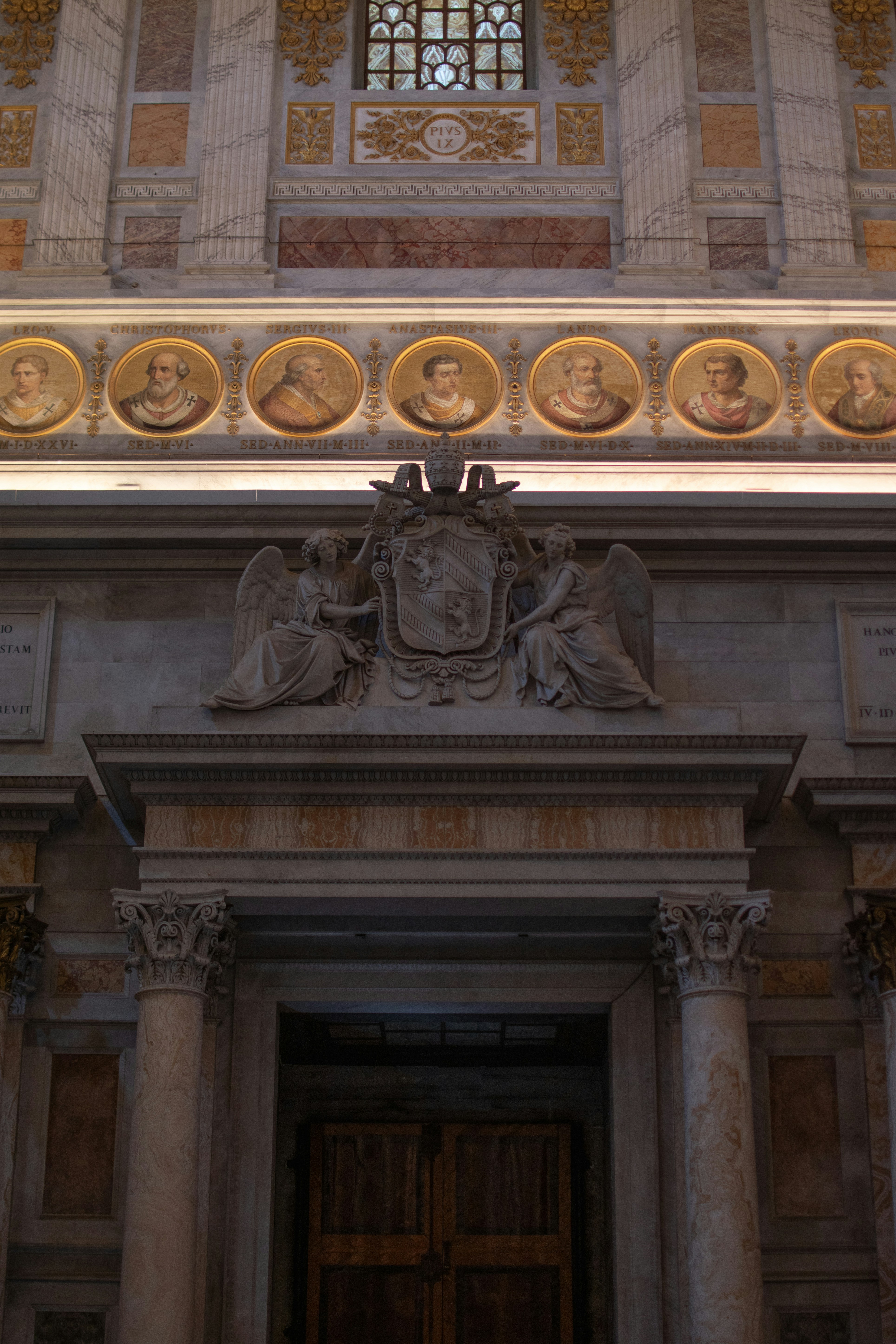 Coat of Arms Over Ornate Portal: Sculpted Emblems Beneath a Ring of Portraits