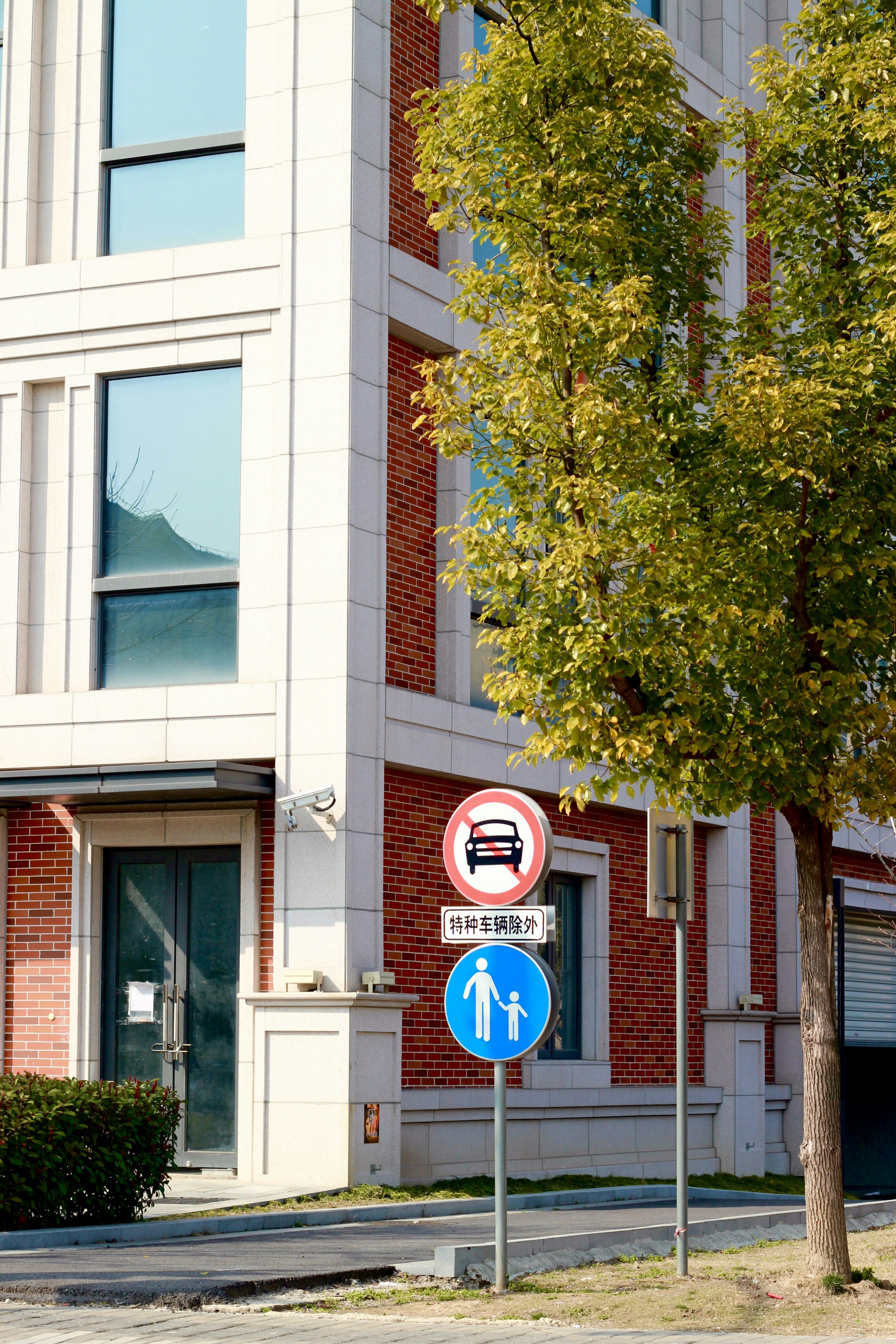 Modern building corner with a tree and two road signs. photo – Free ...