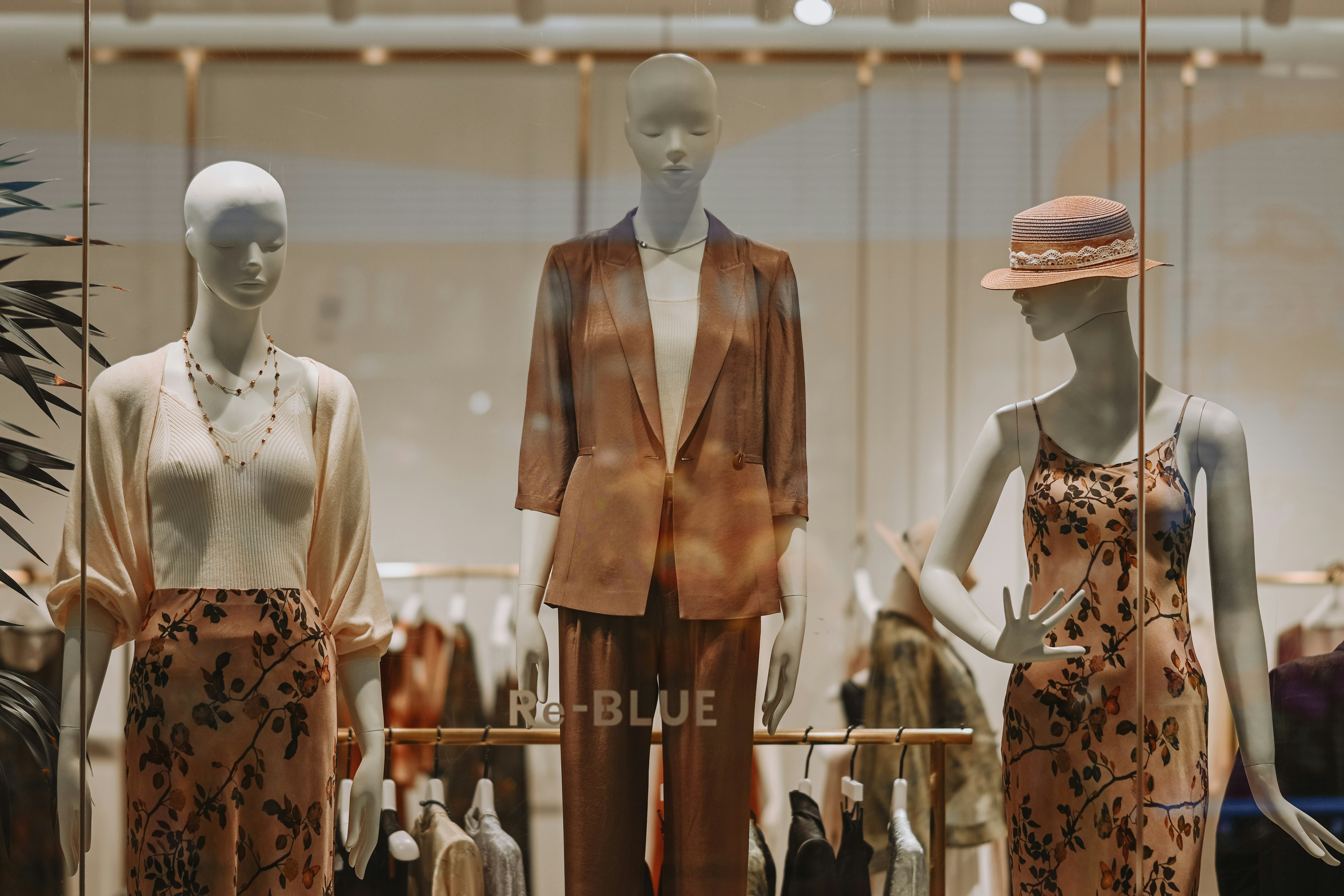 Three mannequins in a boutique window showcasing pastel floral ensembles
