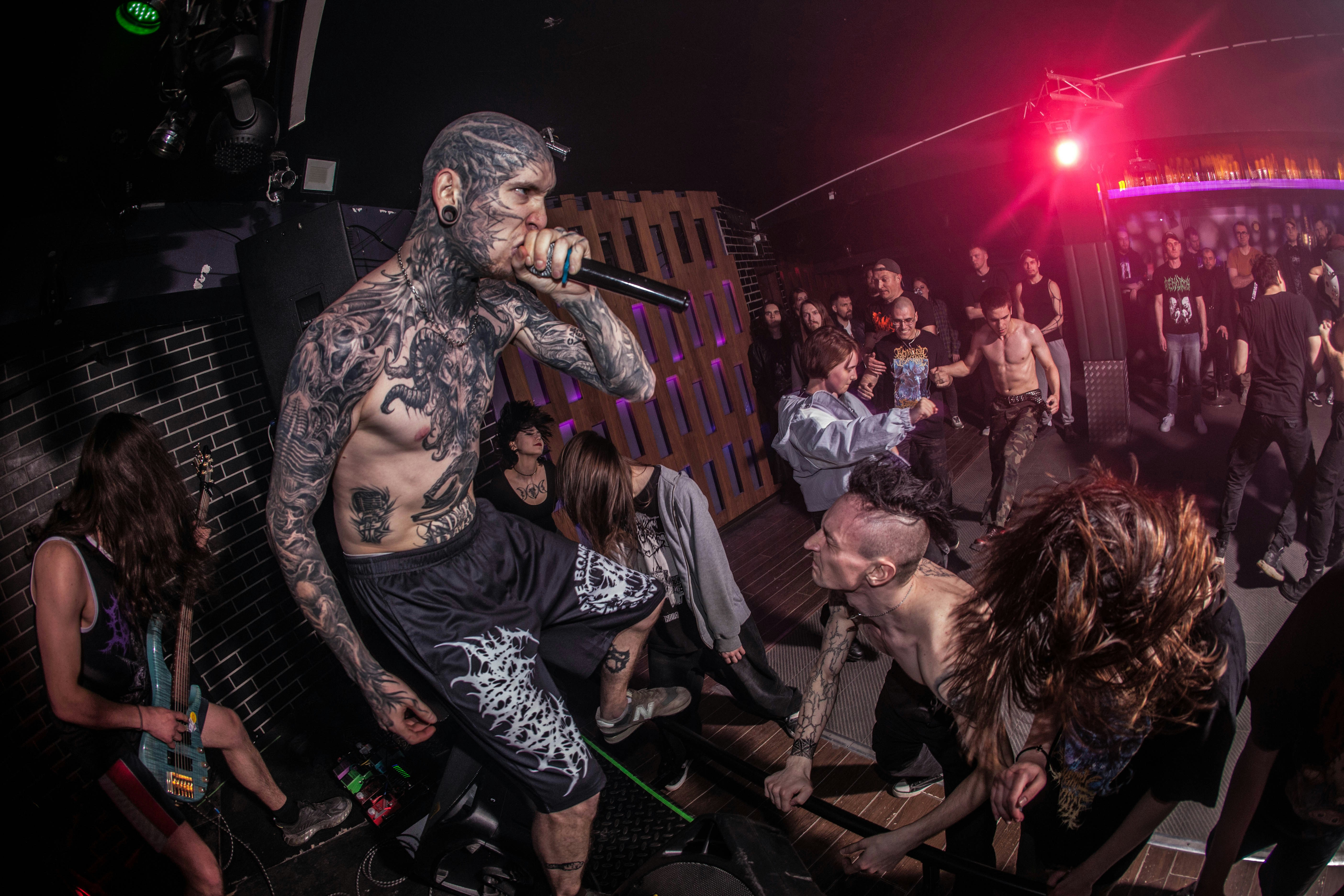 Ink and Echoes: Tattooed vocalist commands the crowded pit under neon glare