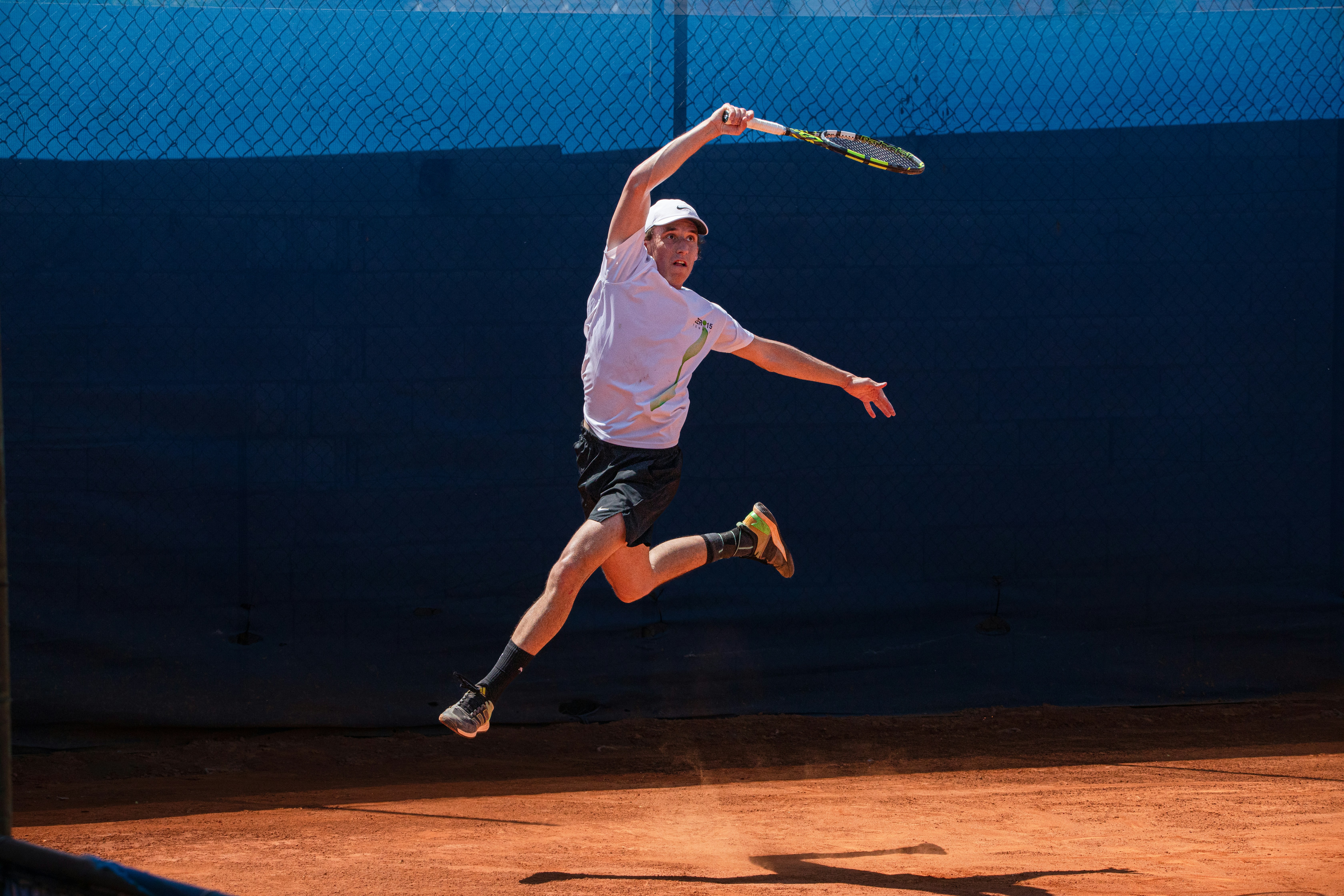 Mid-air Tennis Act: Athlete Soars Against a Copper-Red Court