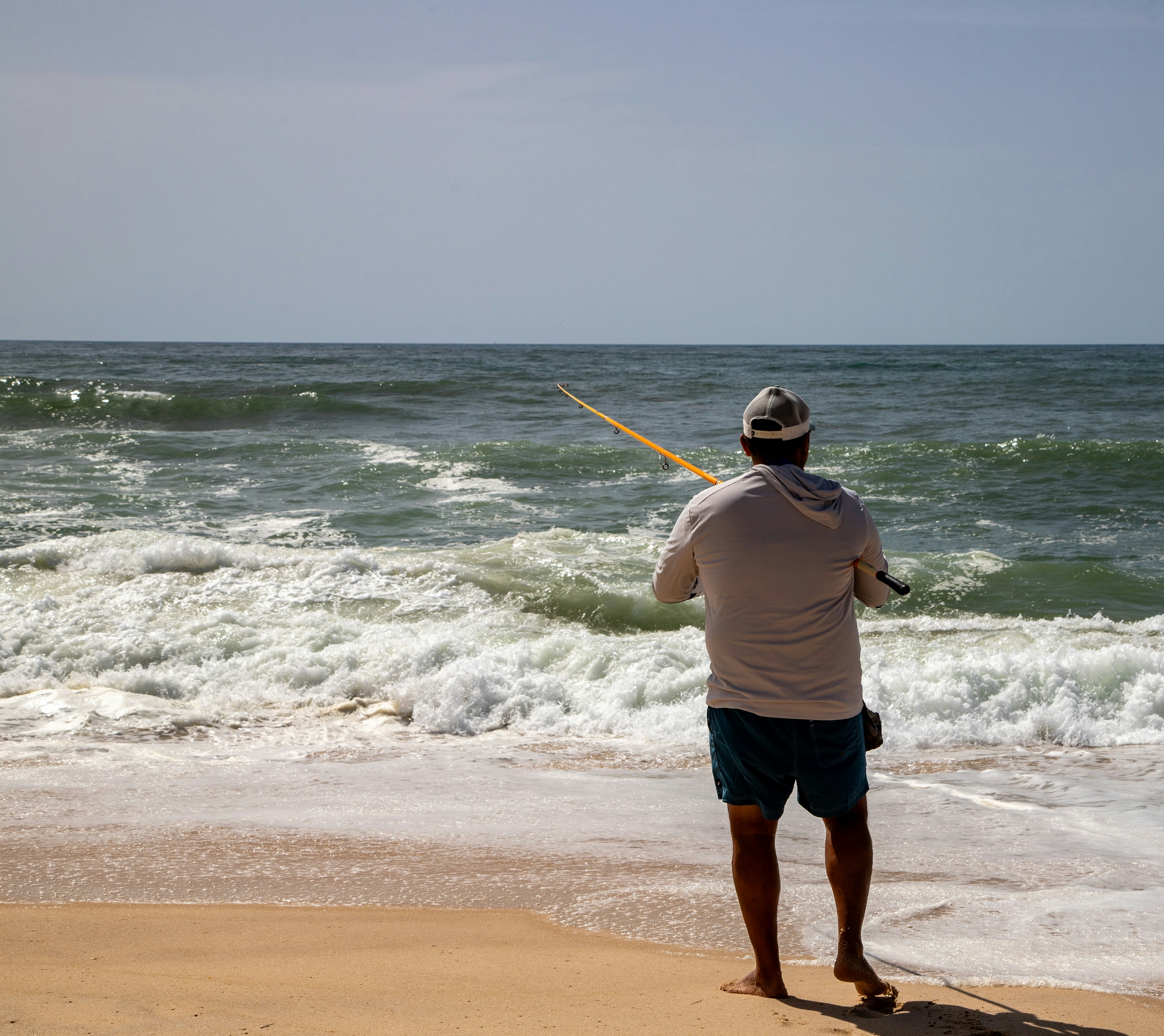 Fisherman casting a line into the wavy ocean.