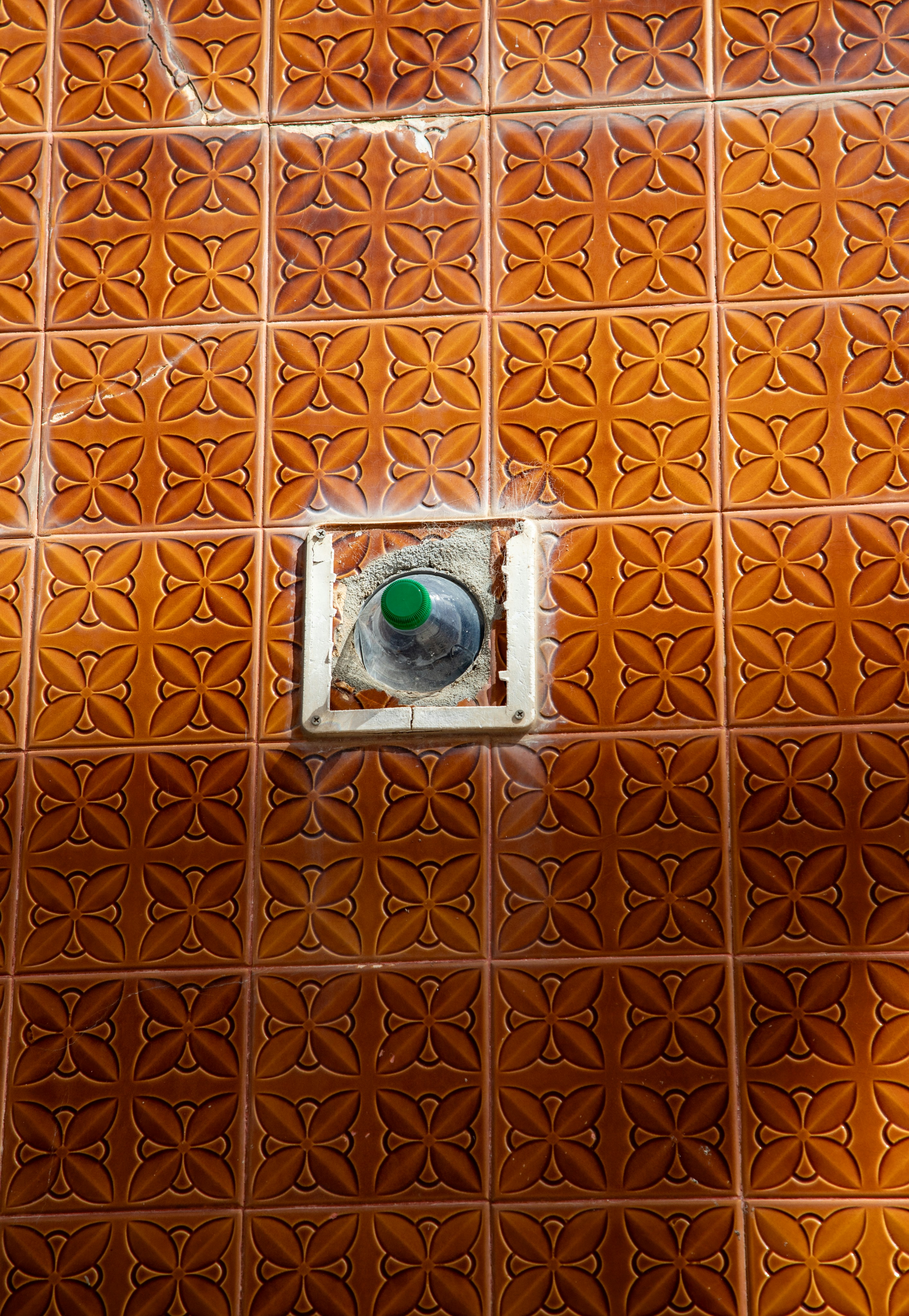 A single green-cap bottle embedded in retro orange tiles