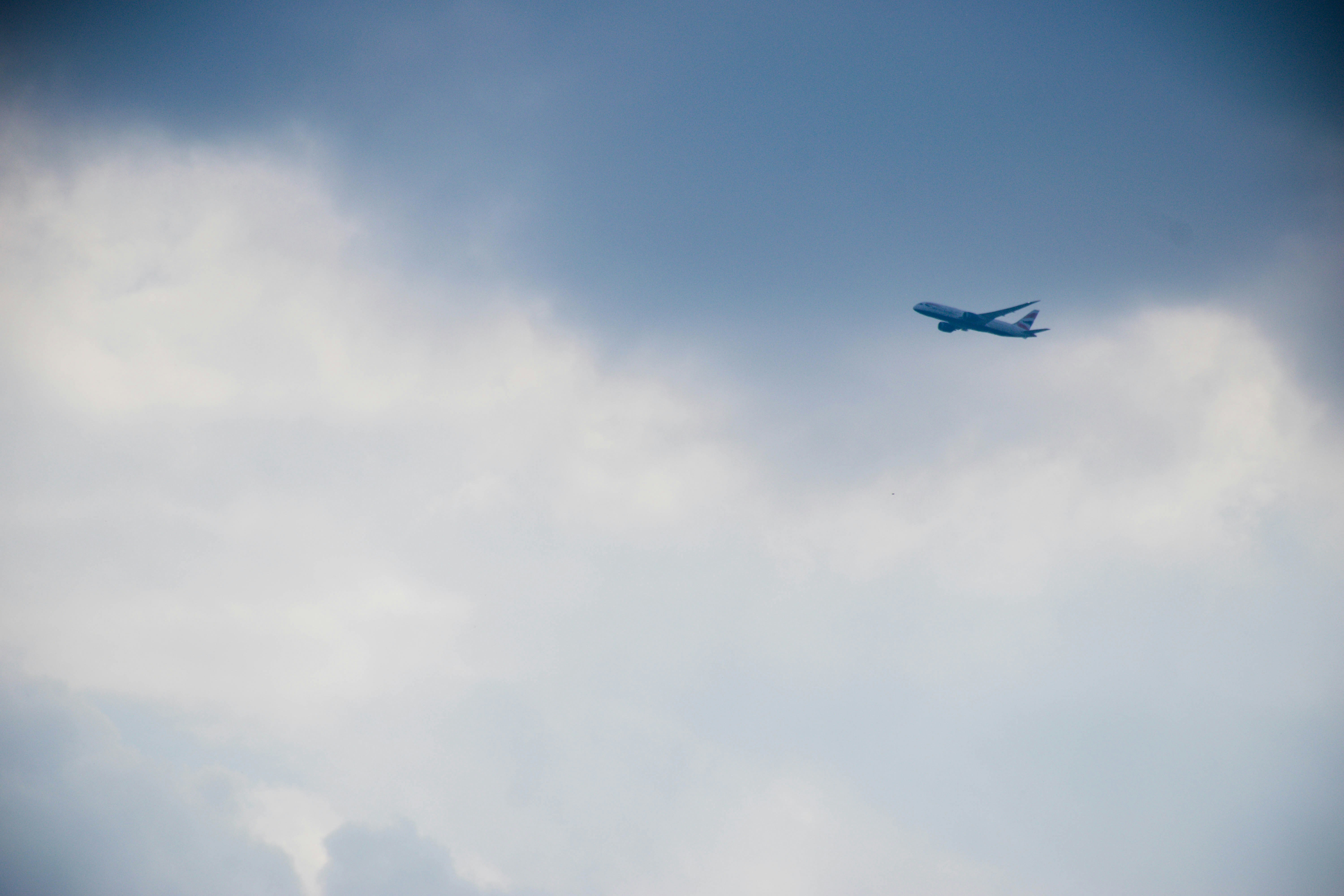 A distant jet tracing a pale sky through drifting clouds