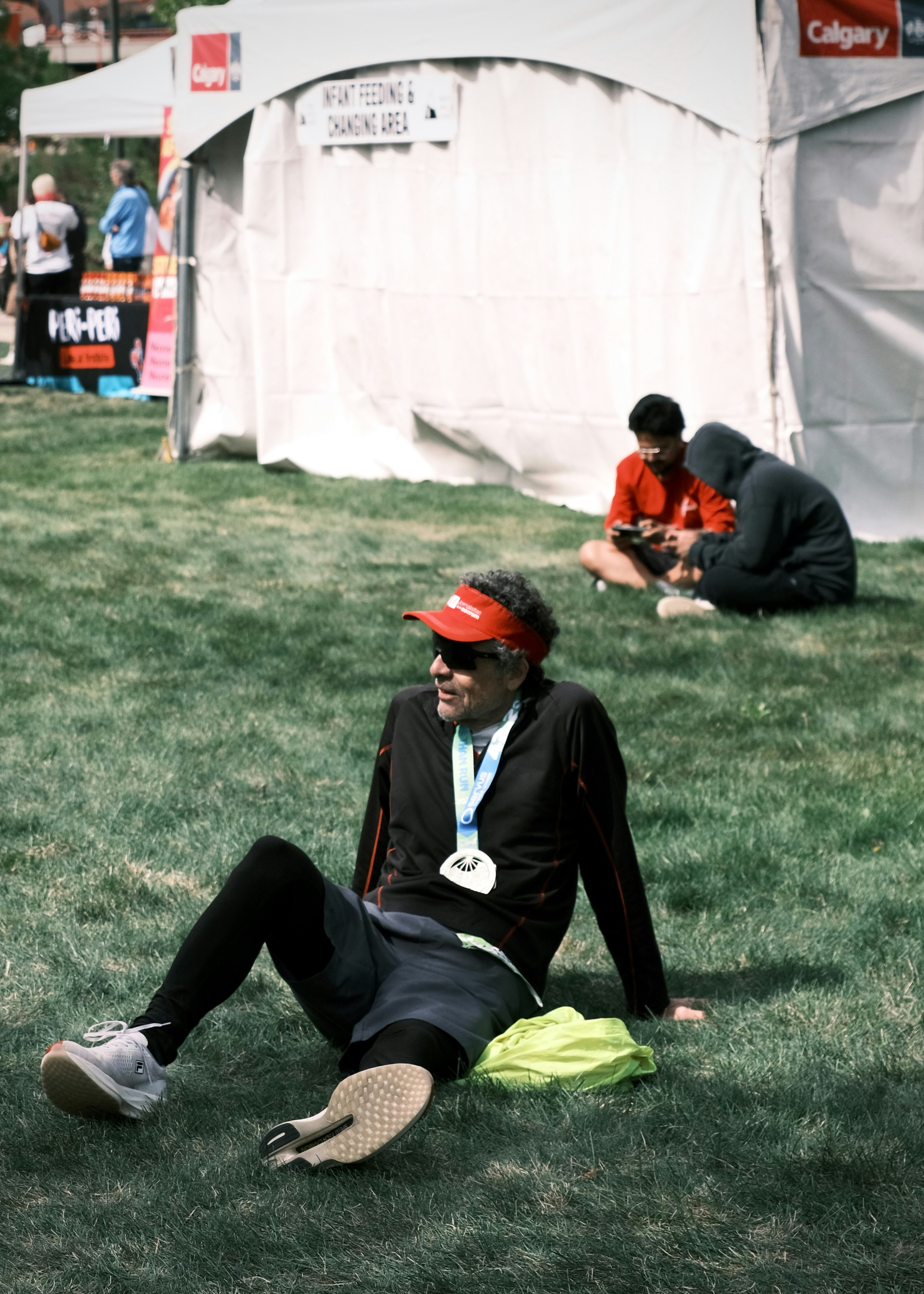 A man wearing a medal sits on the grass.