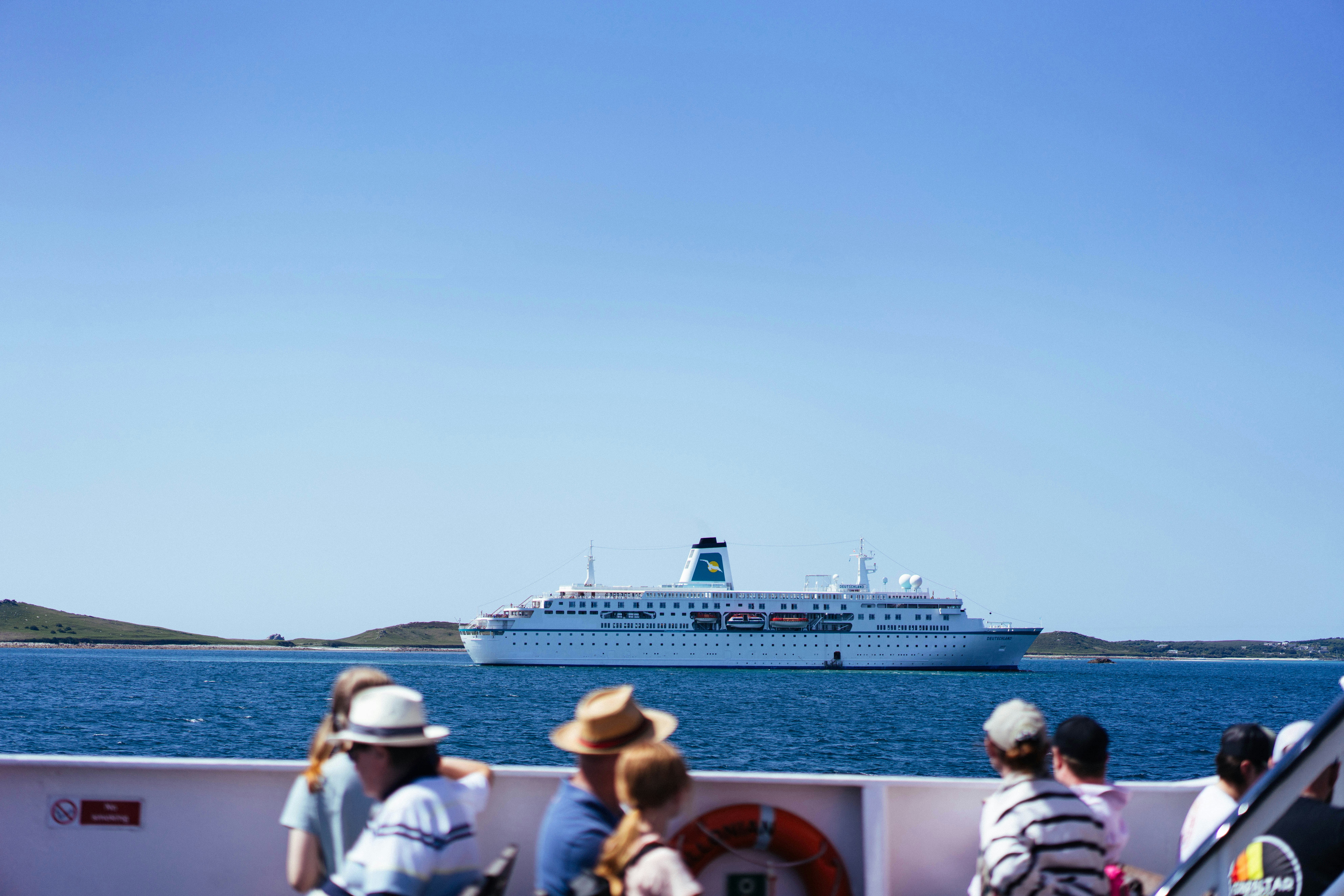 Crossing Horizons: Passengers aboard a ferry gaze toward a distant cruise ship