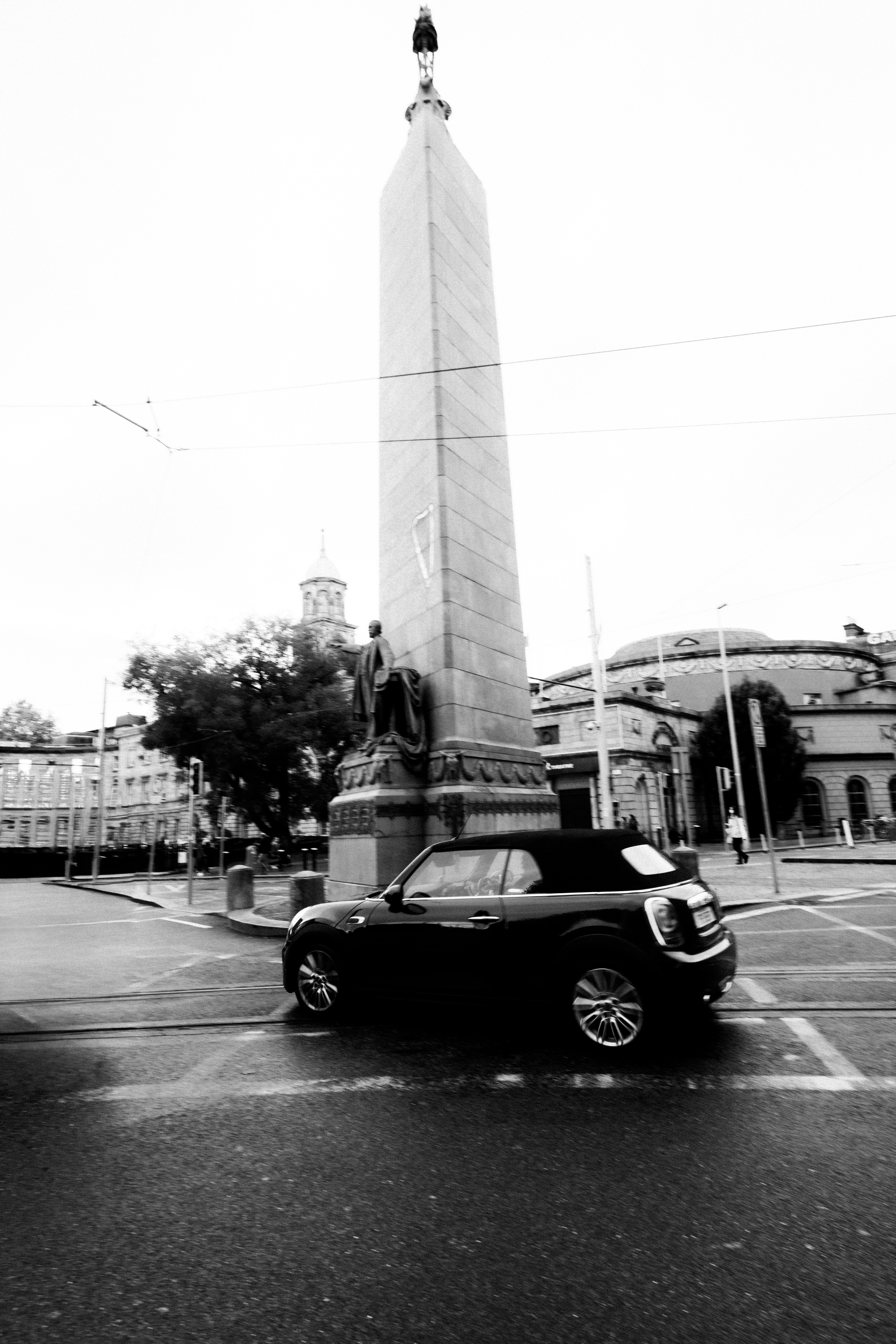 Obelisk vigil: a noir street moment with a compact car at the base
