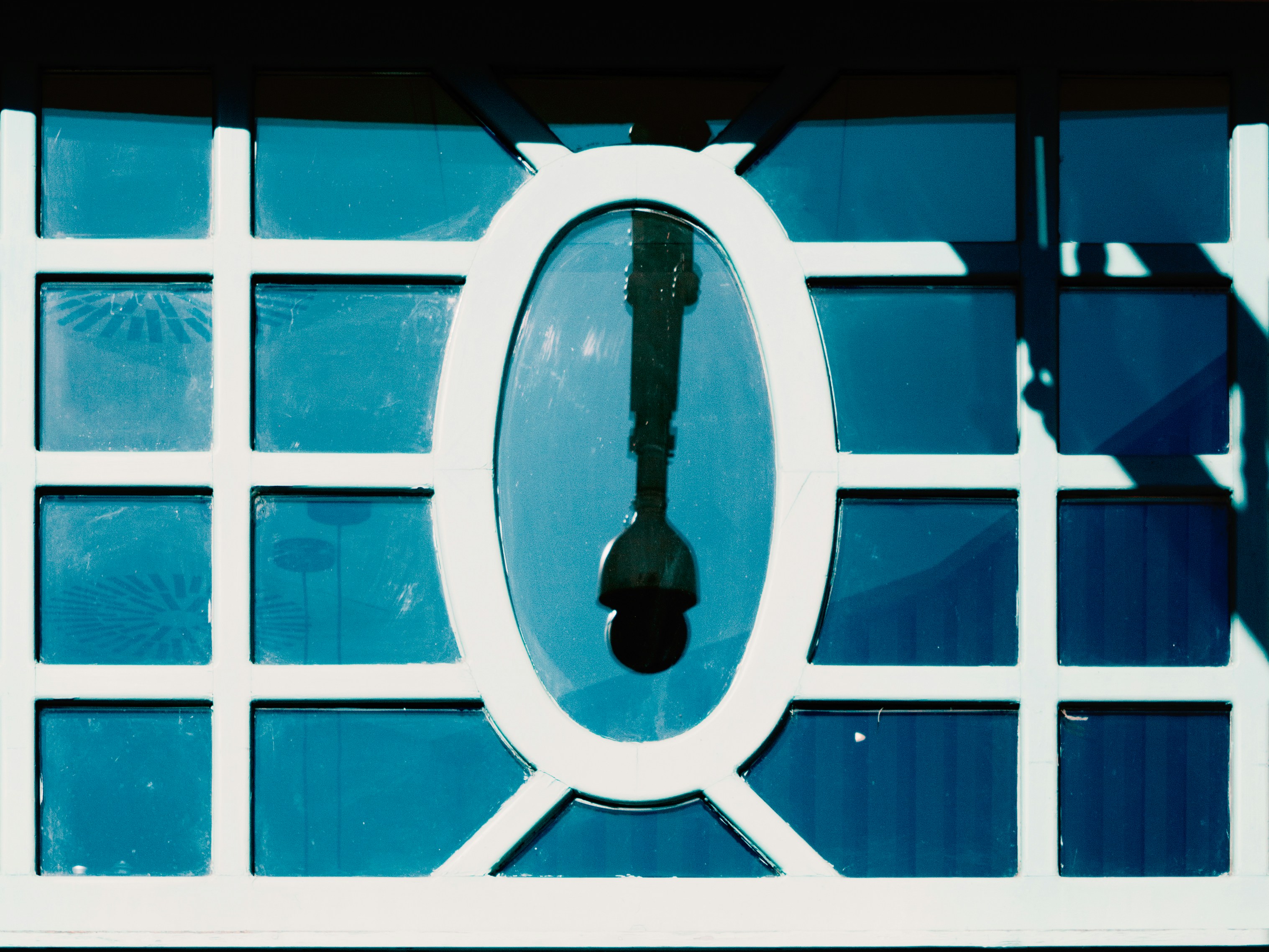 Oval Window Reflection: A Portrait of Symmetry in Glass and Shadow
