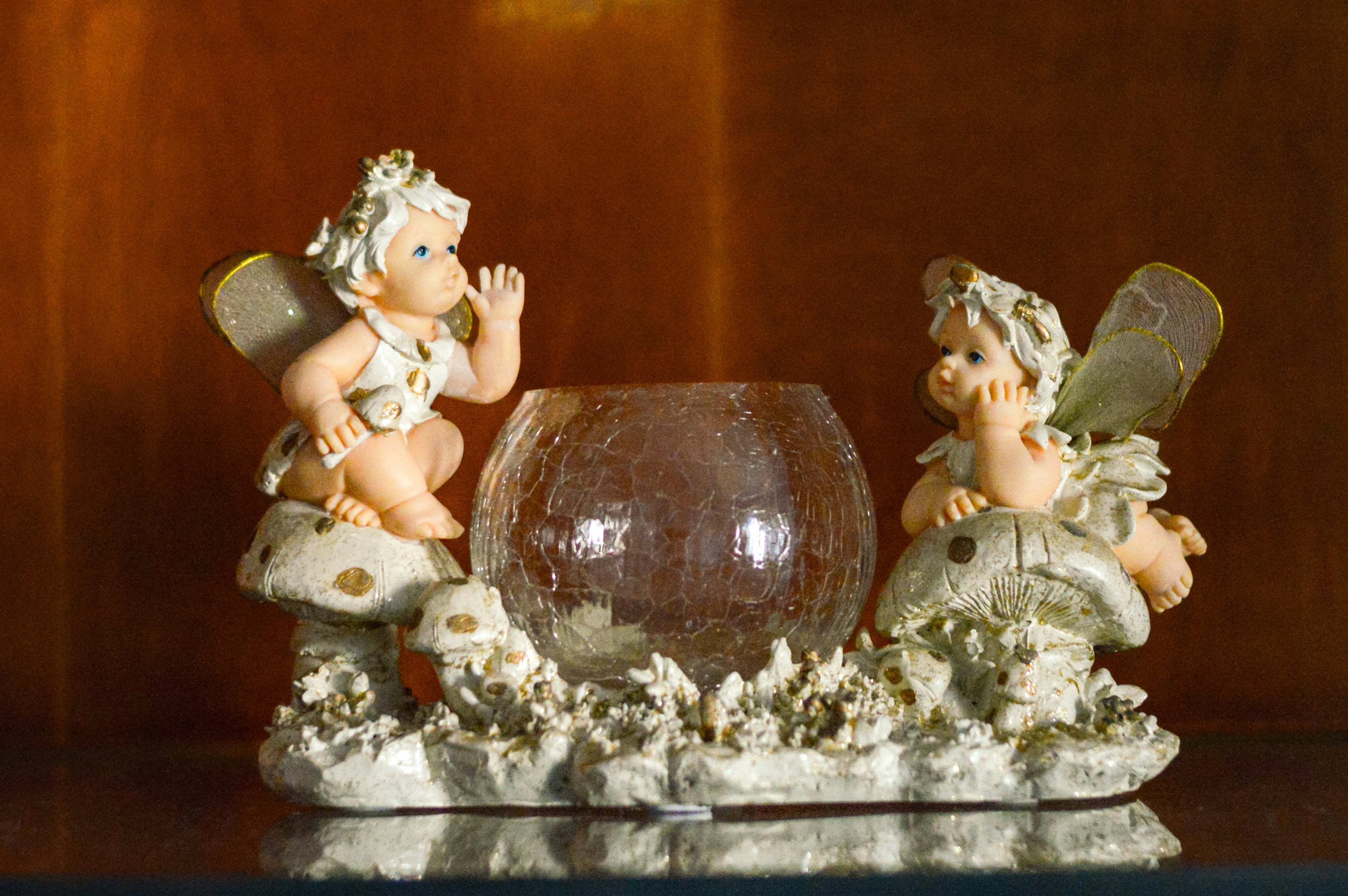 Two cherubim guardians flank a glowing orb candle holder