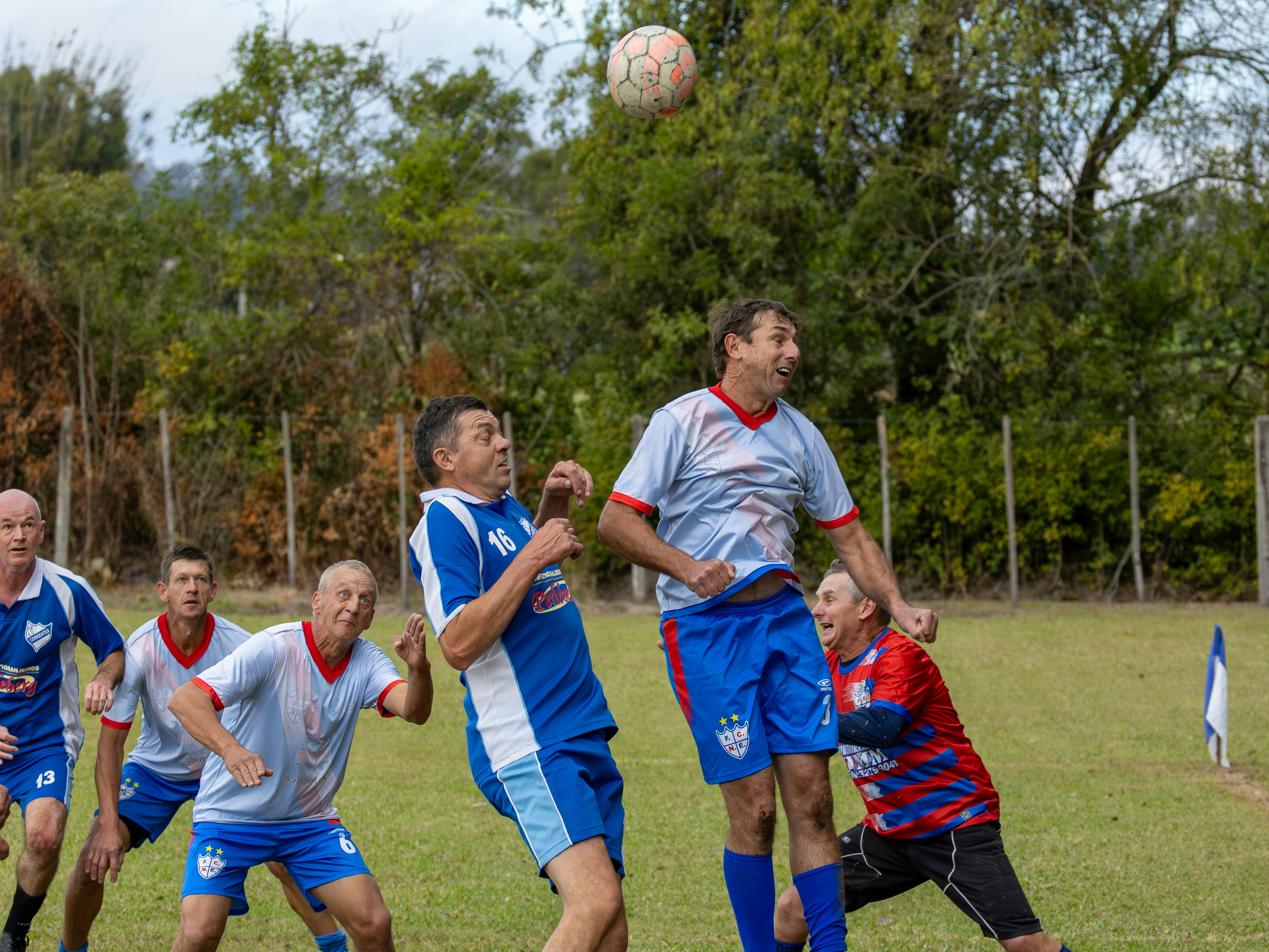 Soccer players jumping to head the ball during a game.