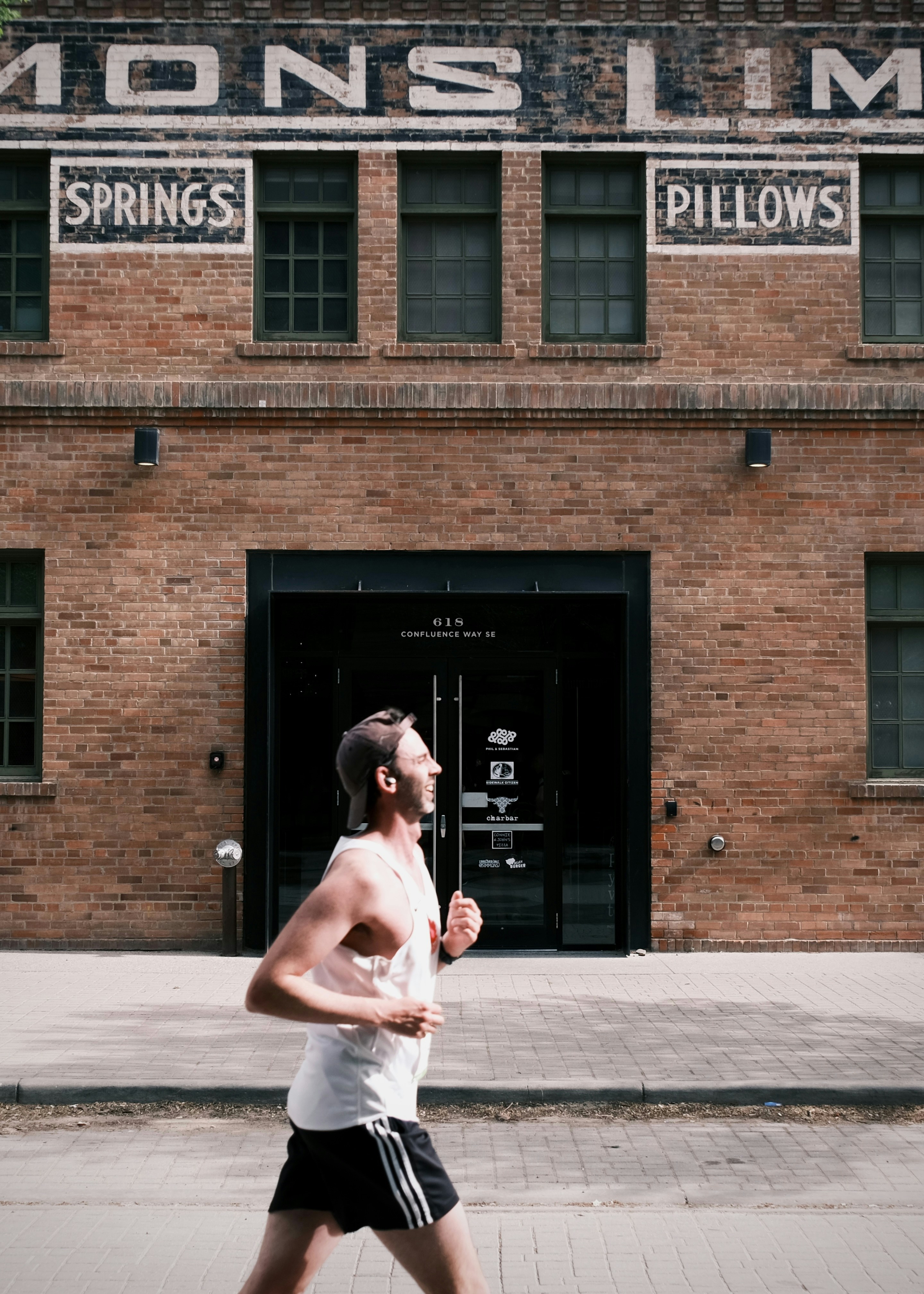 Runner in Front of Brick Factory: A Moment of Motion on a City Street