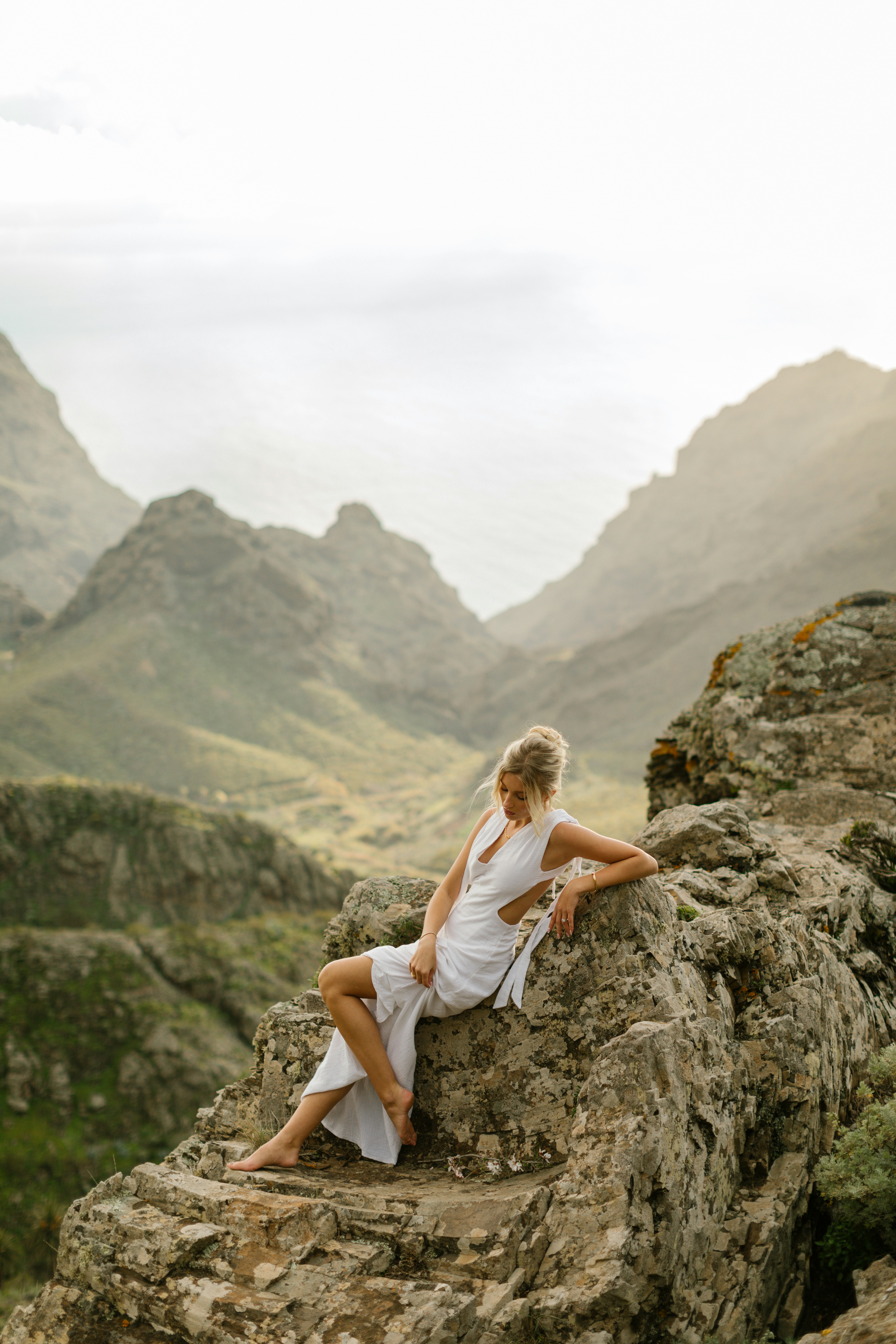 Cliffside Quiet: A Woman Resting Among Fjord-like Peaks at Golden Hour