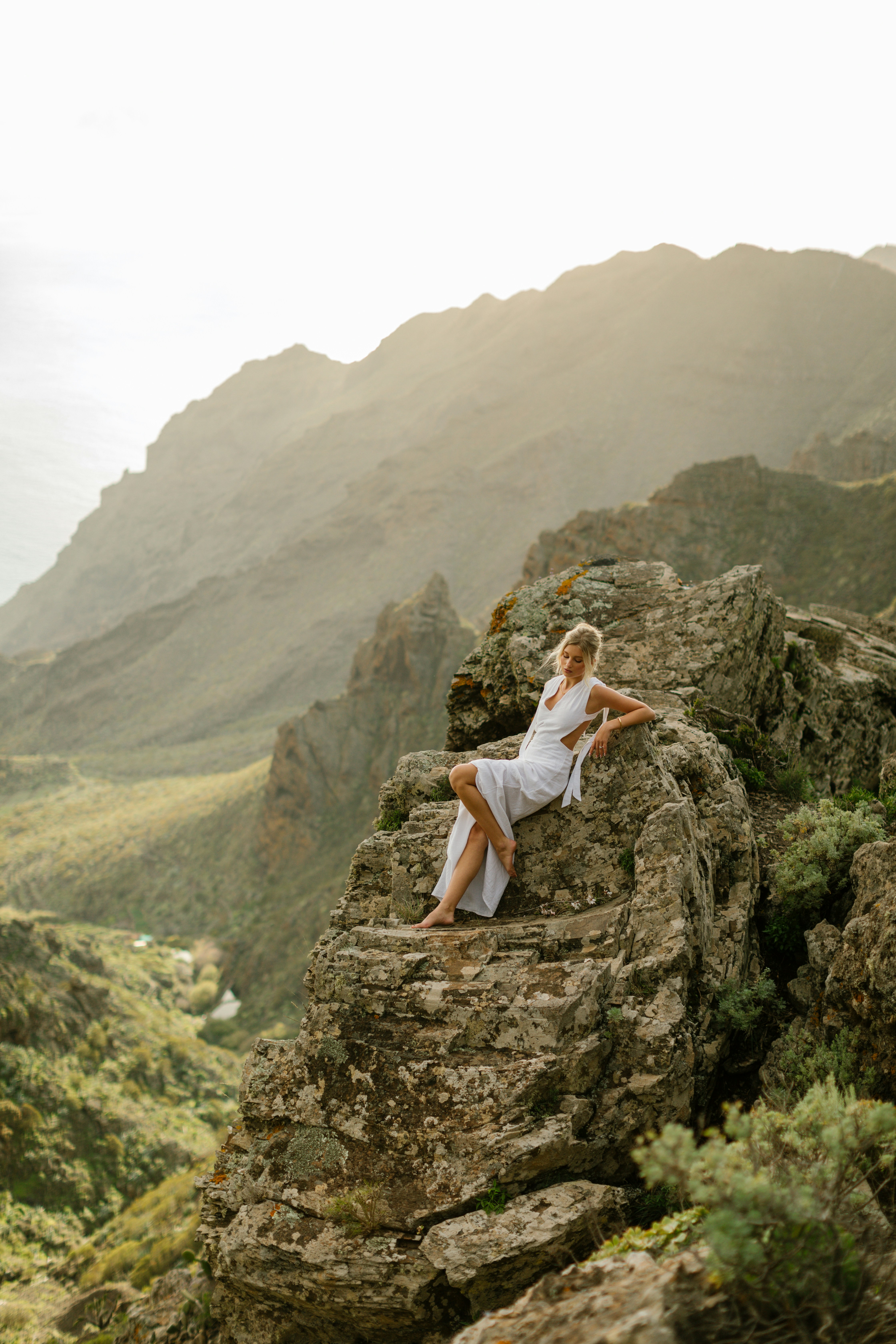 Cliffside Solace: A Woman in White Finds Balance on a Rugged Promontory