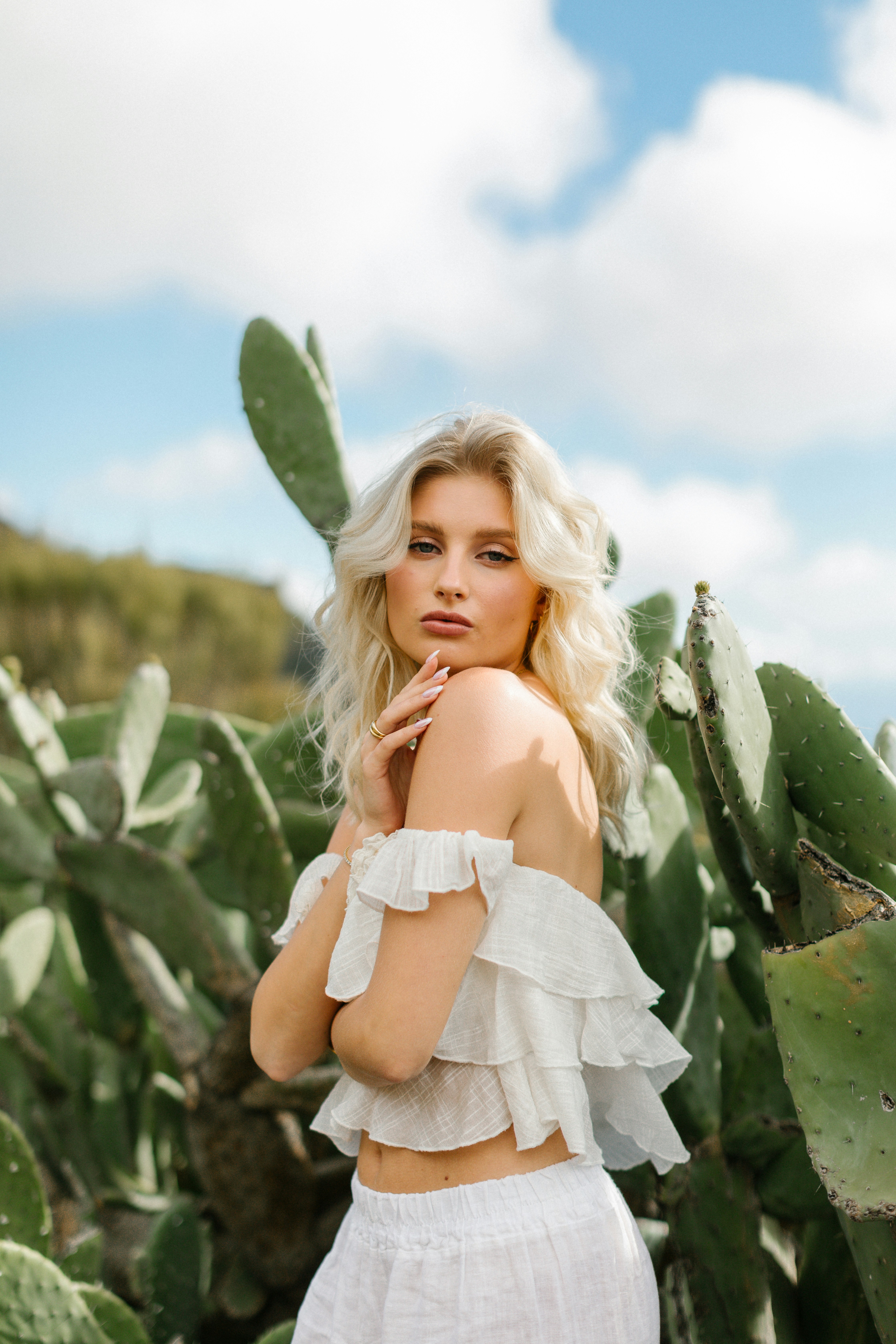 Blonde Amidst Cardboard Cacti: Soft Light on a White Off-Shoulder Portrait