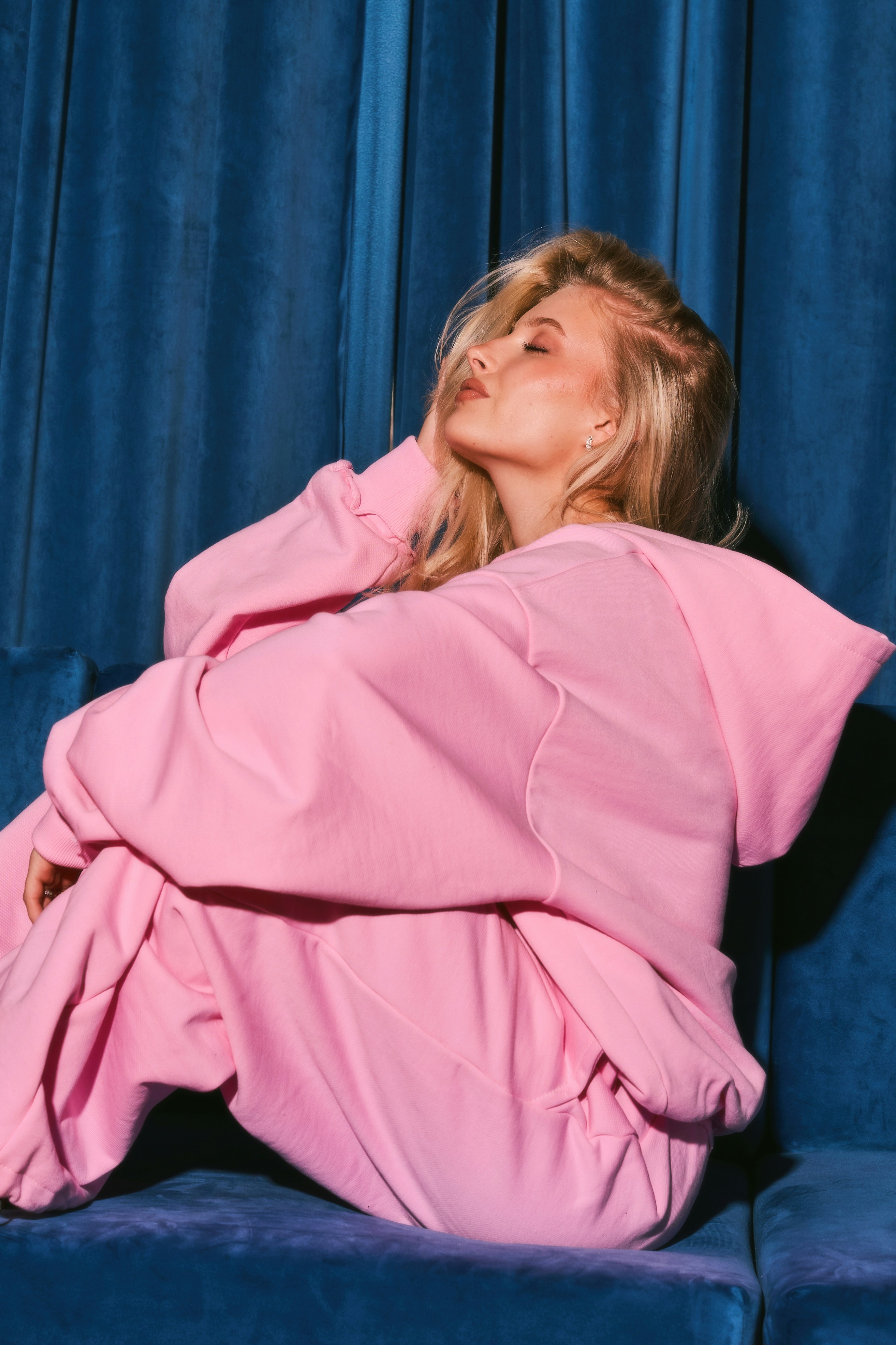 Lilac Snug: A Velvet Pose Against Blue Curtain