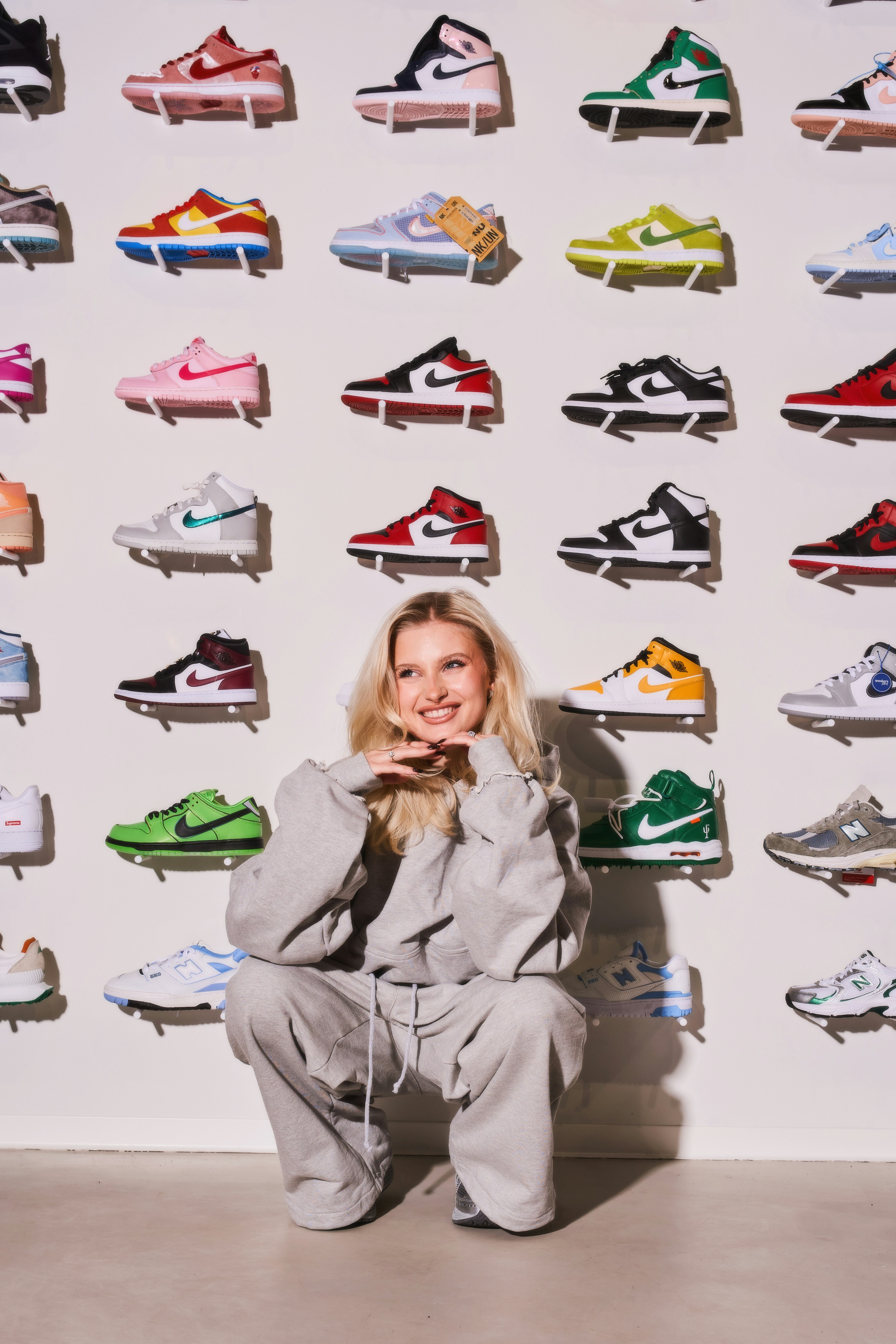 Playful Pose Beneath a Wall of Sneakers