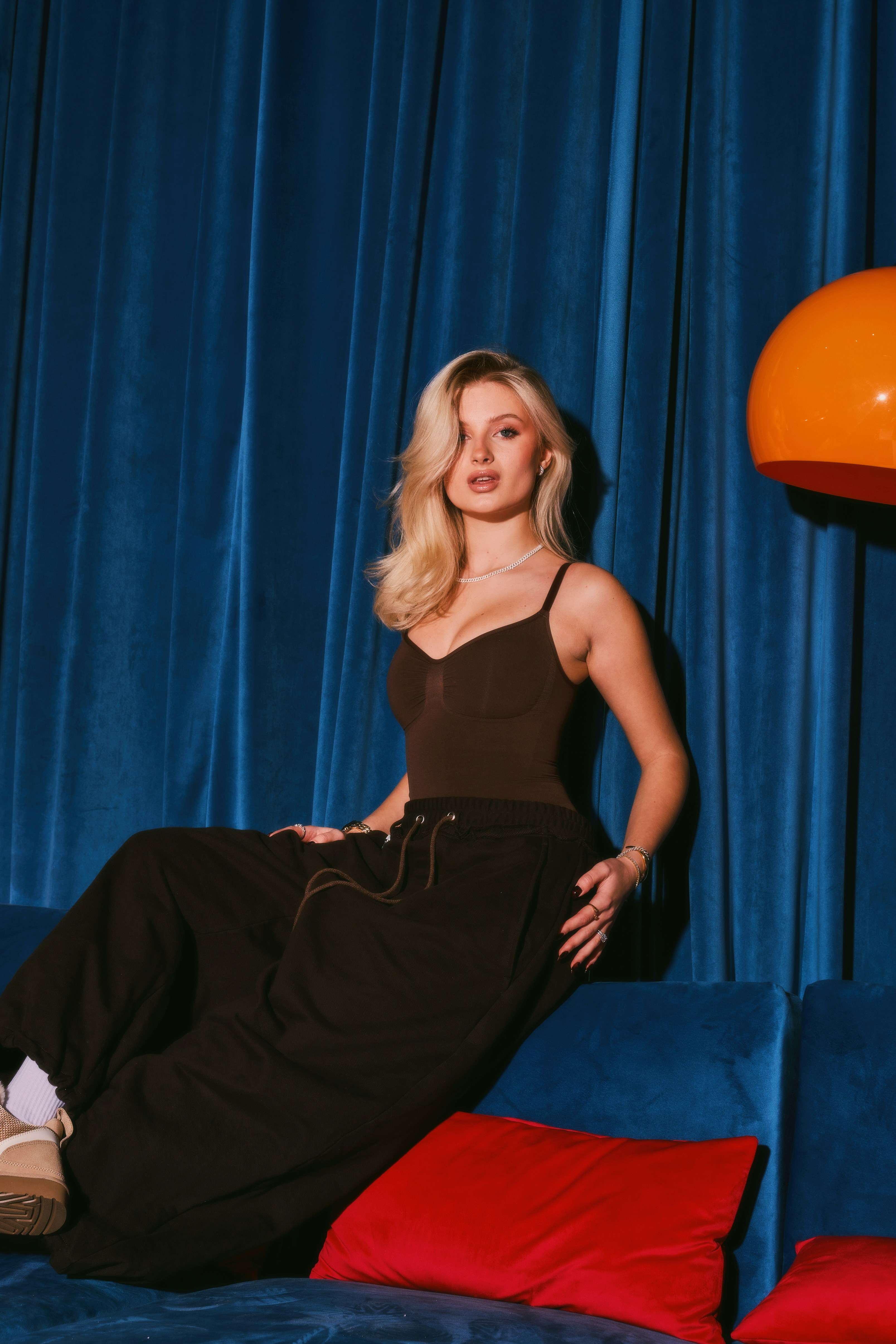 Blonde confidante in cobalt velvet: a poised stare on a midnight sofa
