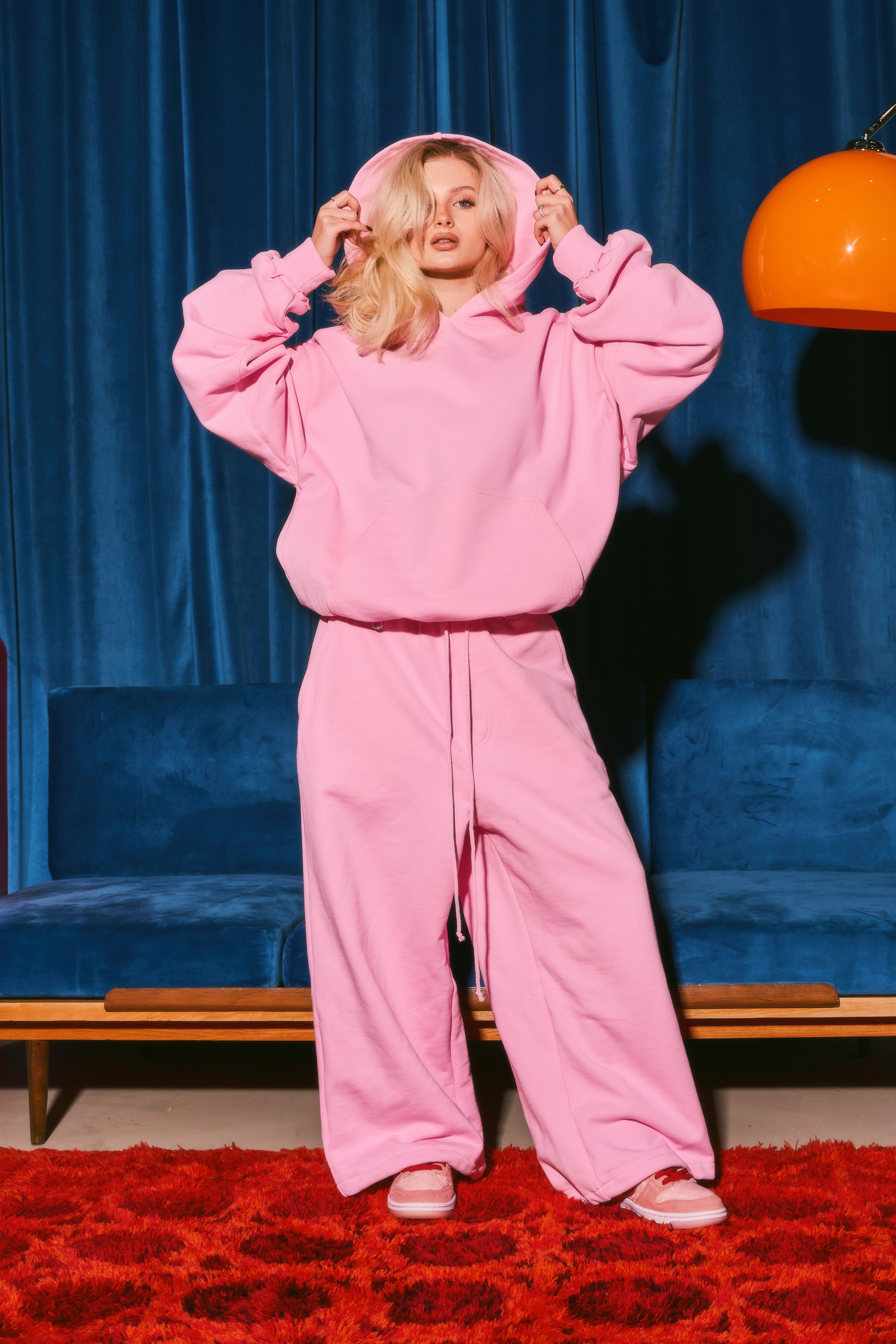 Pink hoodie, blue backdrop: a casual portrait in a retro lounge