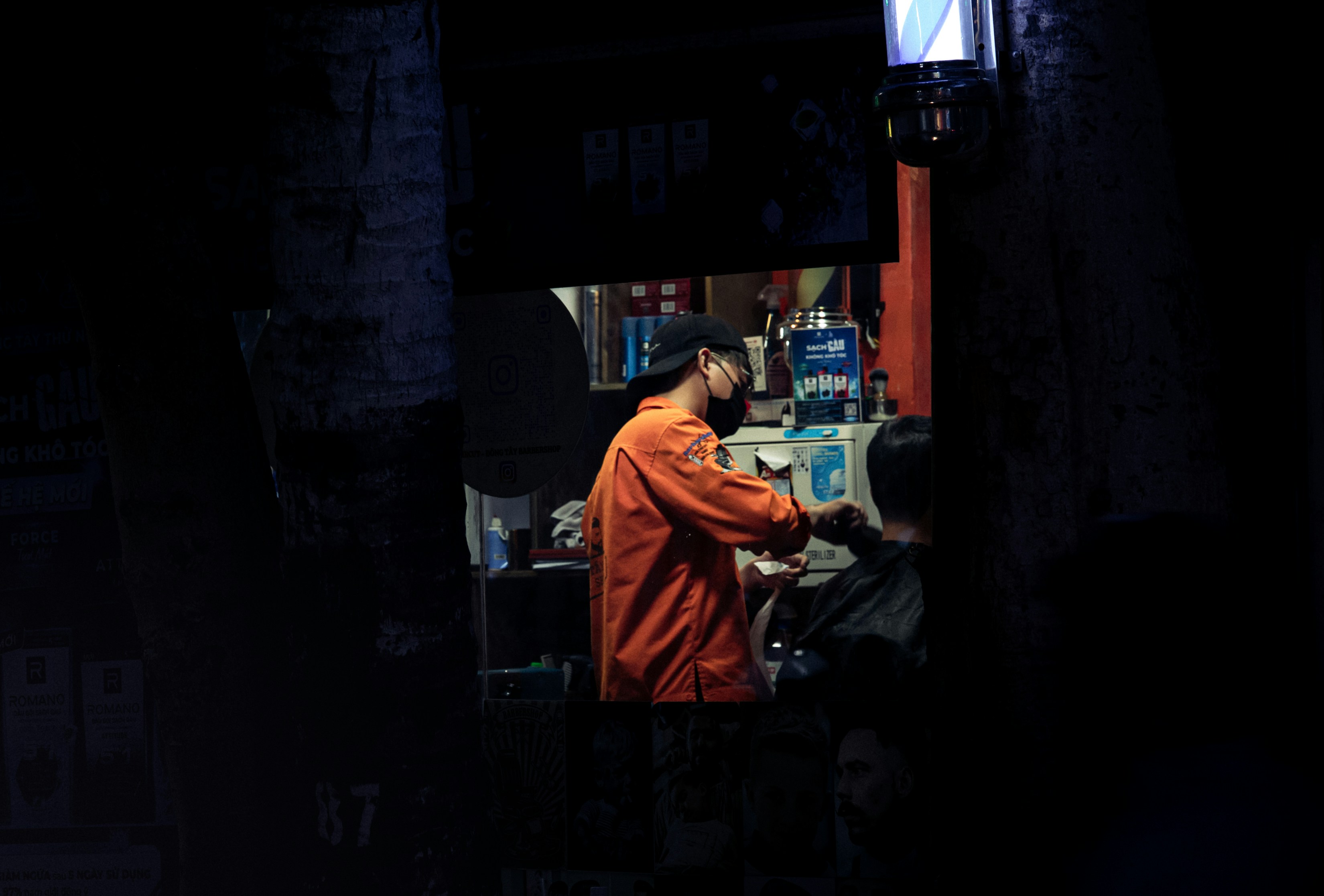 Orange Jacket in a Backlit Barber Shop: A Quiet Corridor of Focus