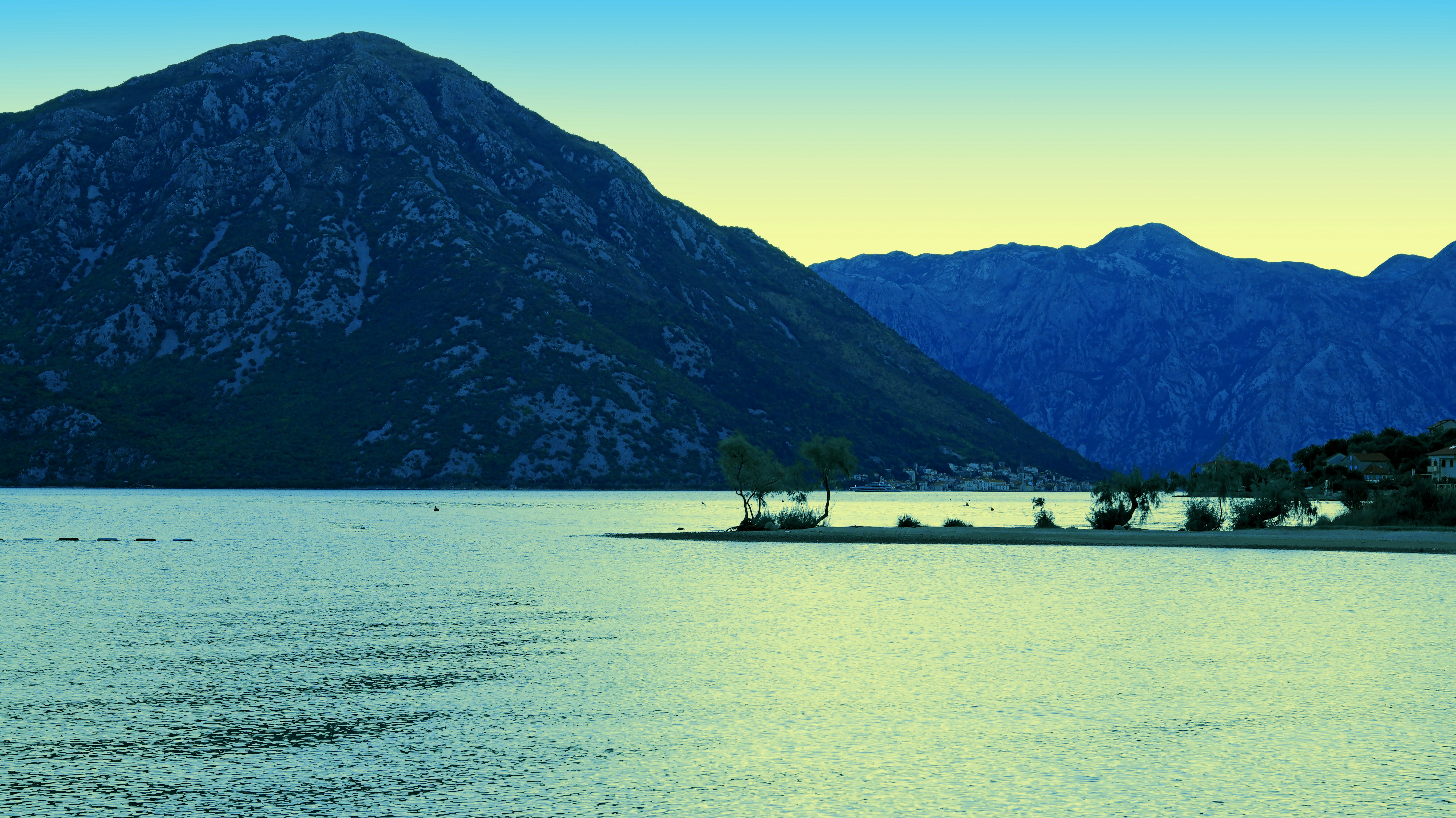 Sunlit Fjord Quiet: Mountains, Lake, and a Narrow Shoreline