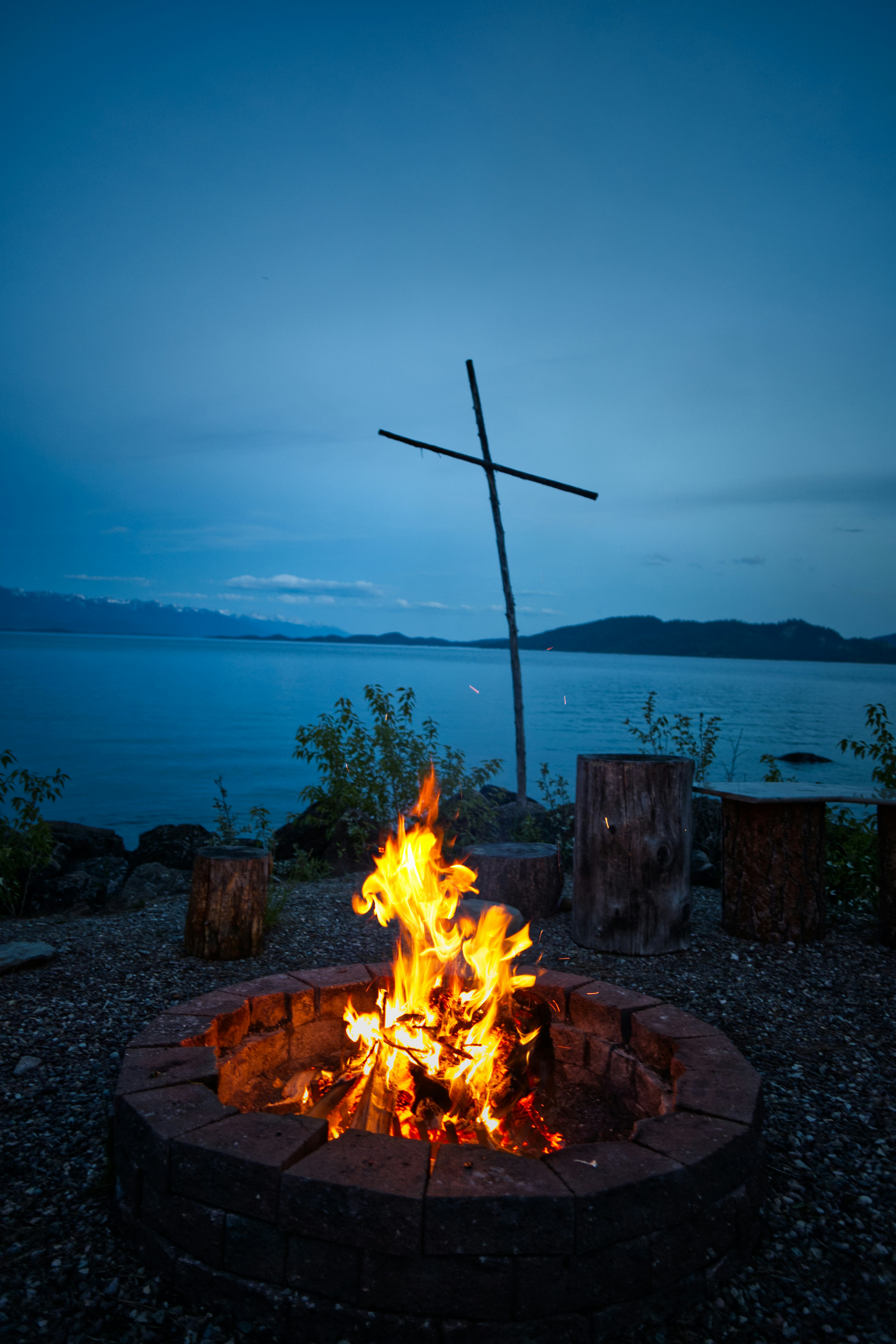 Flames on the Shore: a Lone Cross Over a Quiet Fjord