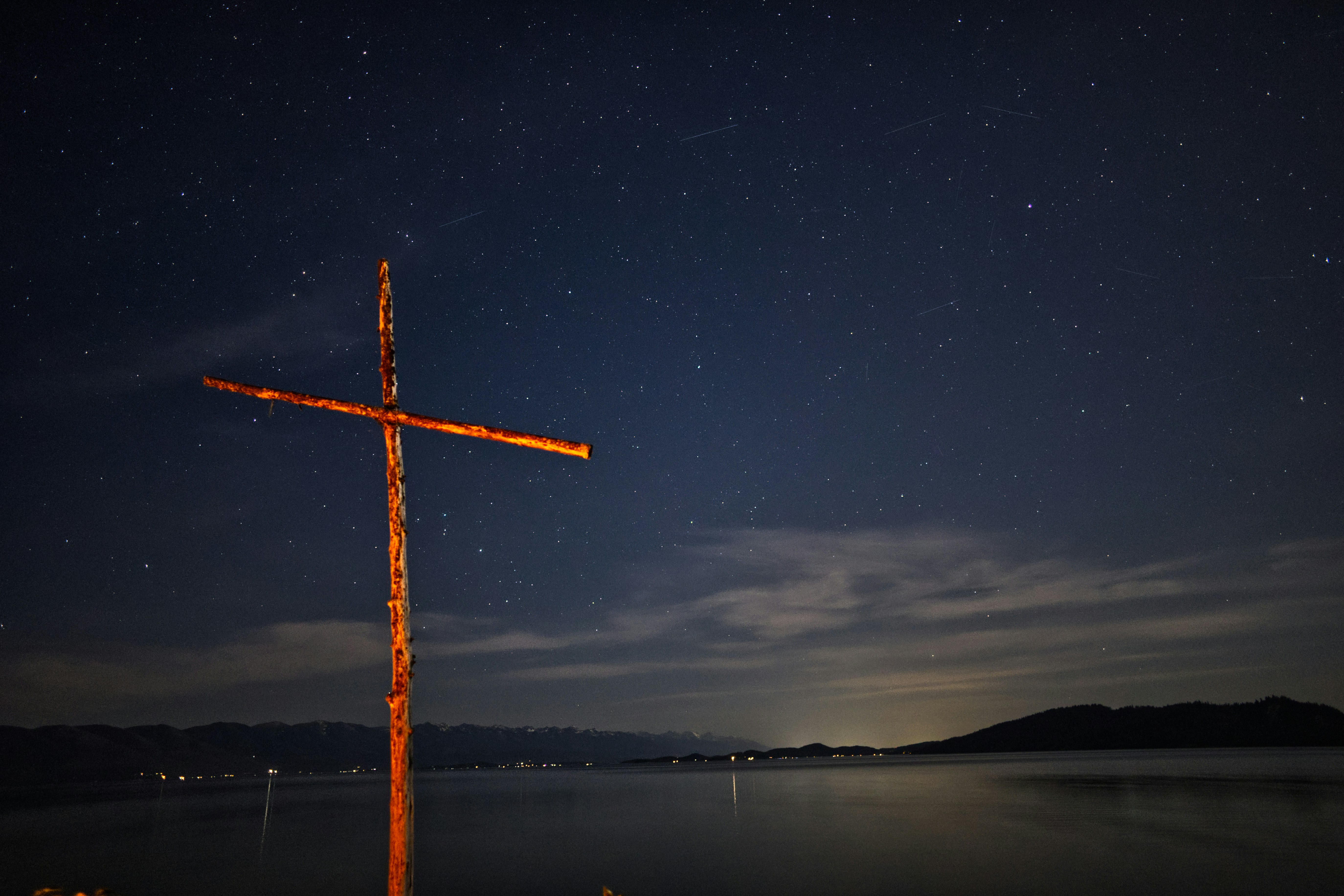 Silent Sentinel: A Rust-Colored Cross Under a Starfield Night