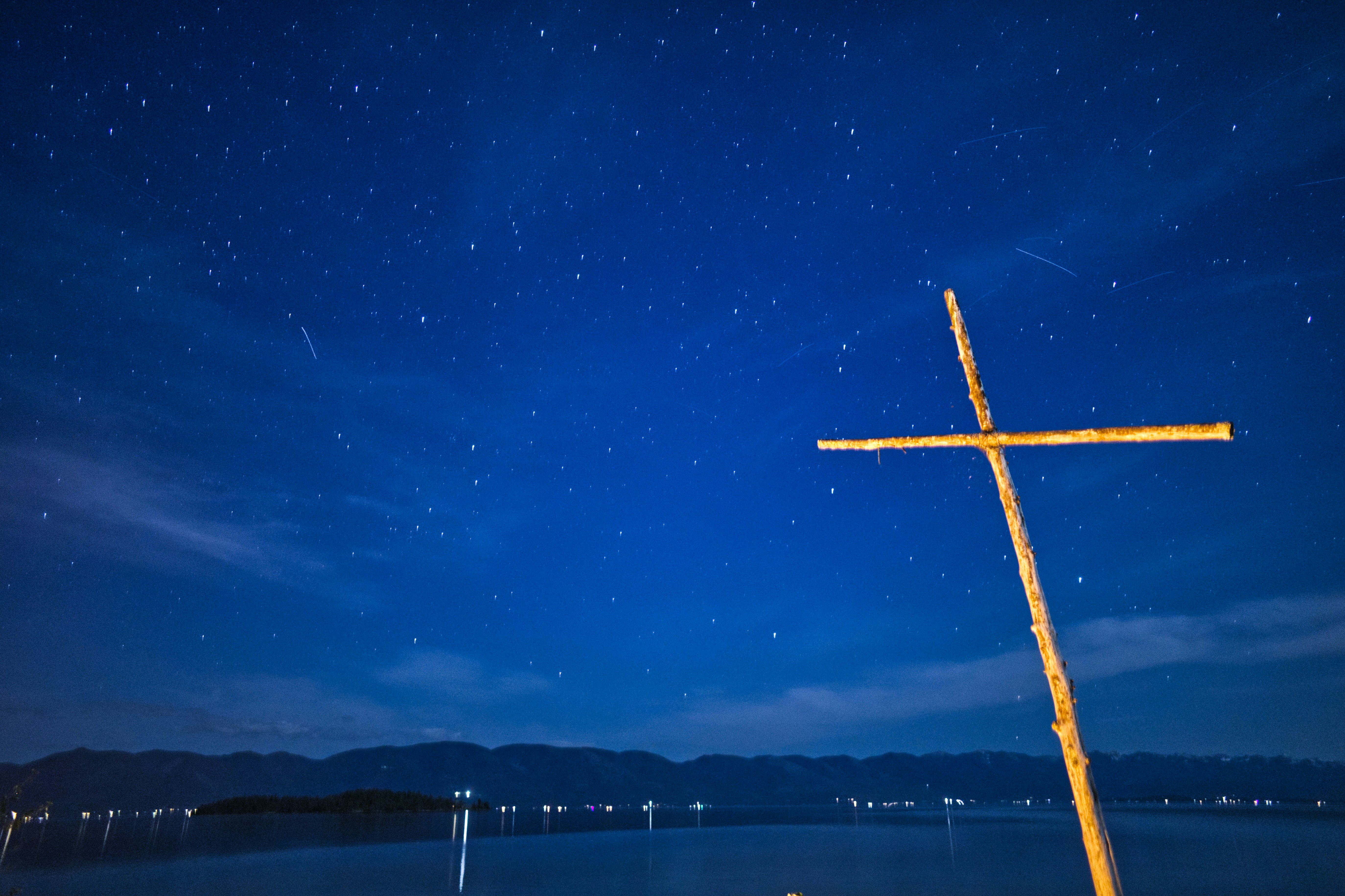 Starry Cross: Night Sky over a Calm Lake with a Wooden Symbol