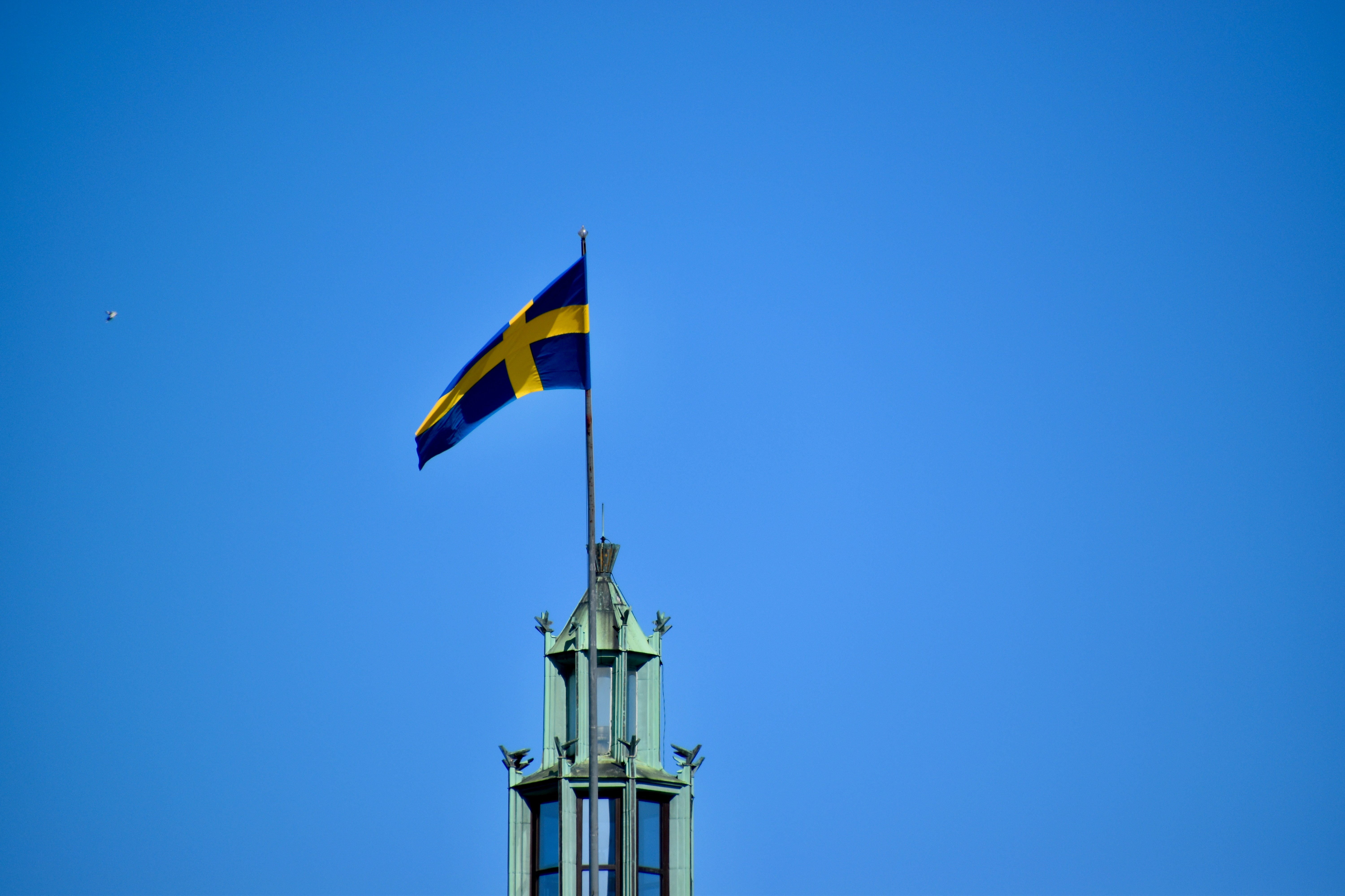 Swedish Flag atop Gothic Spire Against Cerulean Sky