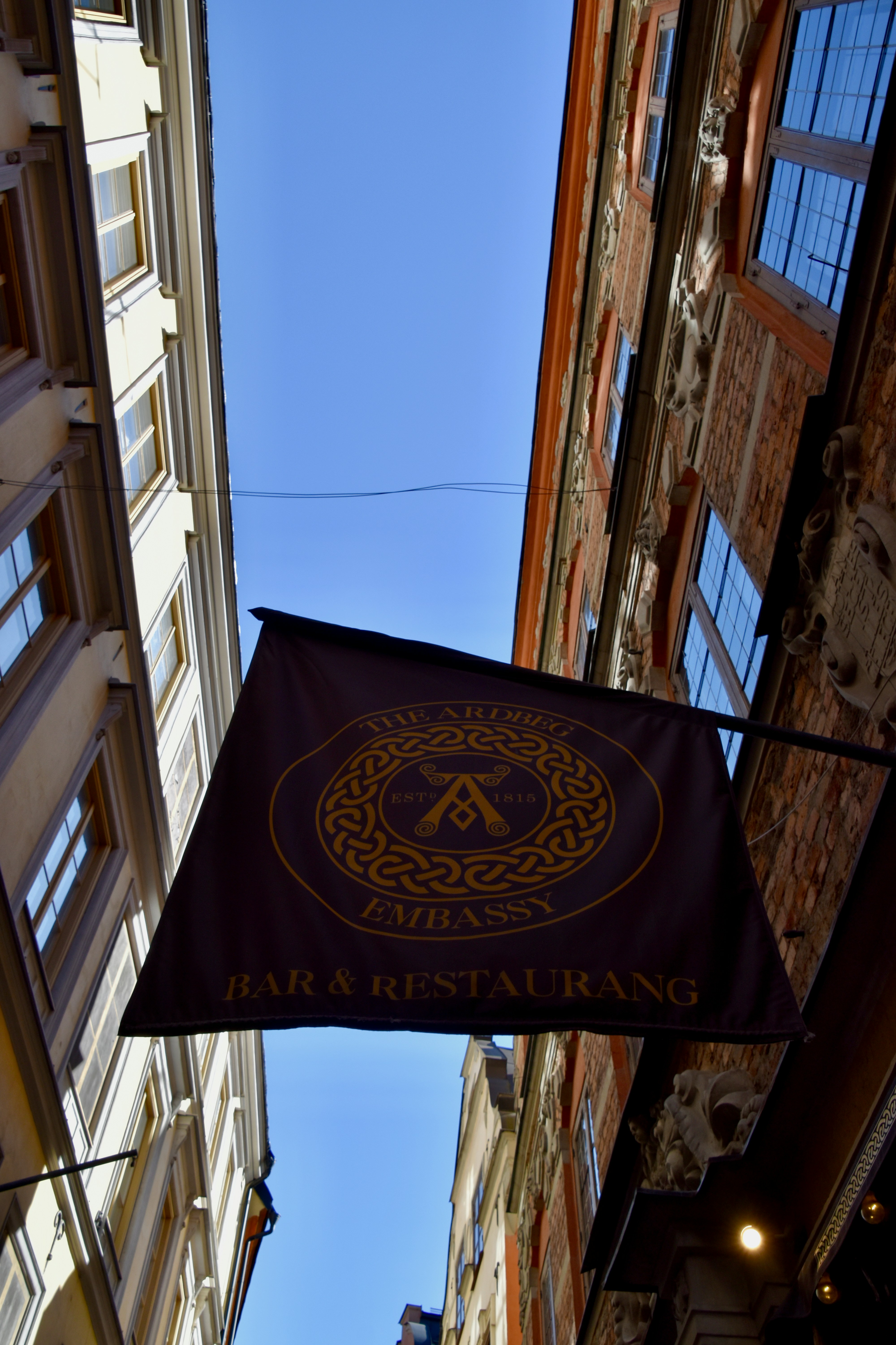 Narrow Sky and Sign: A Café Banner Between Old Buildings