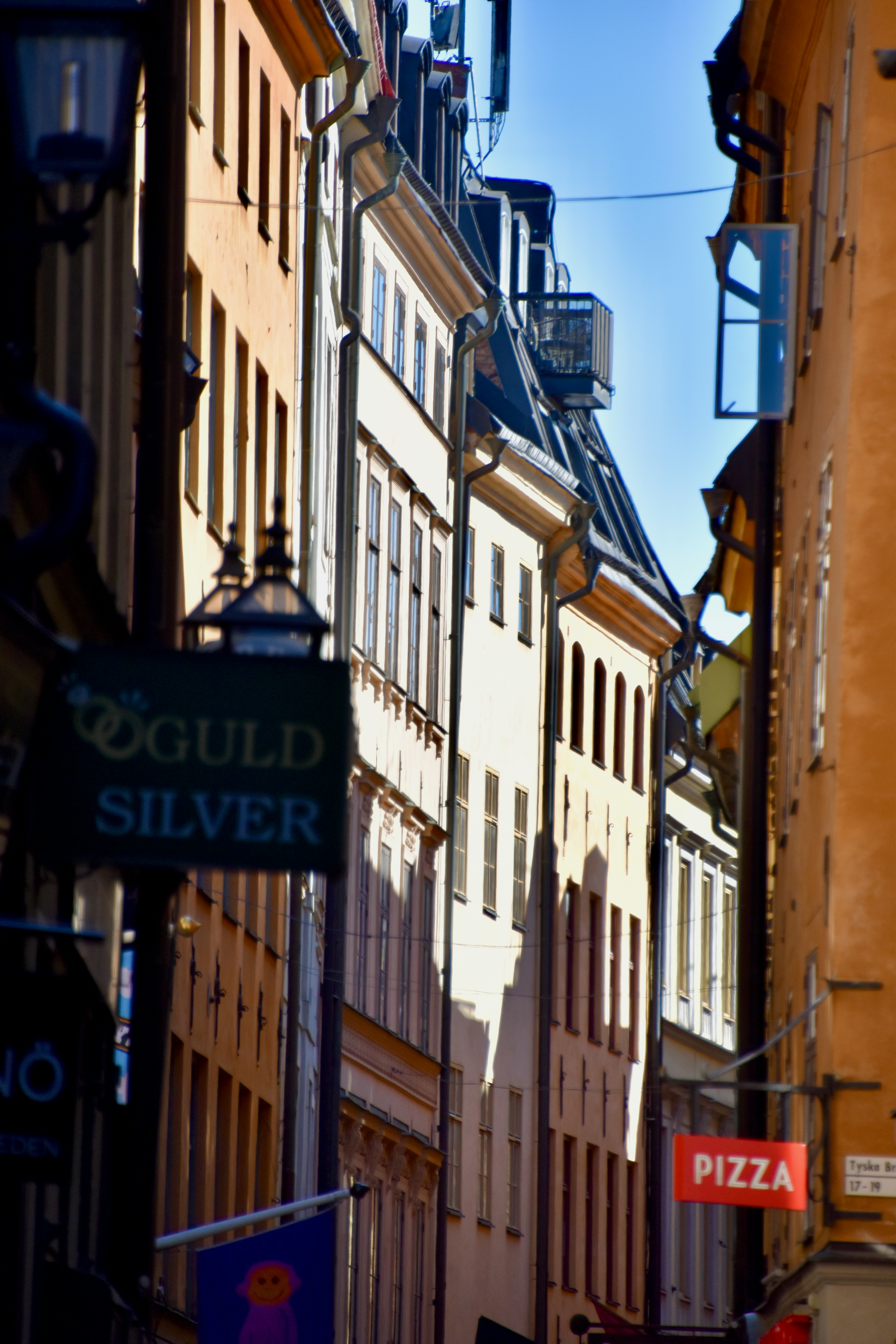 Sunlit Alleyway: A European Street Ebbing with Color and Signage