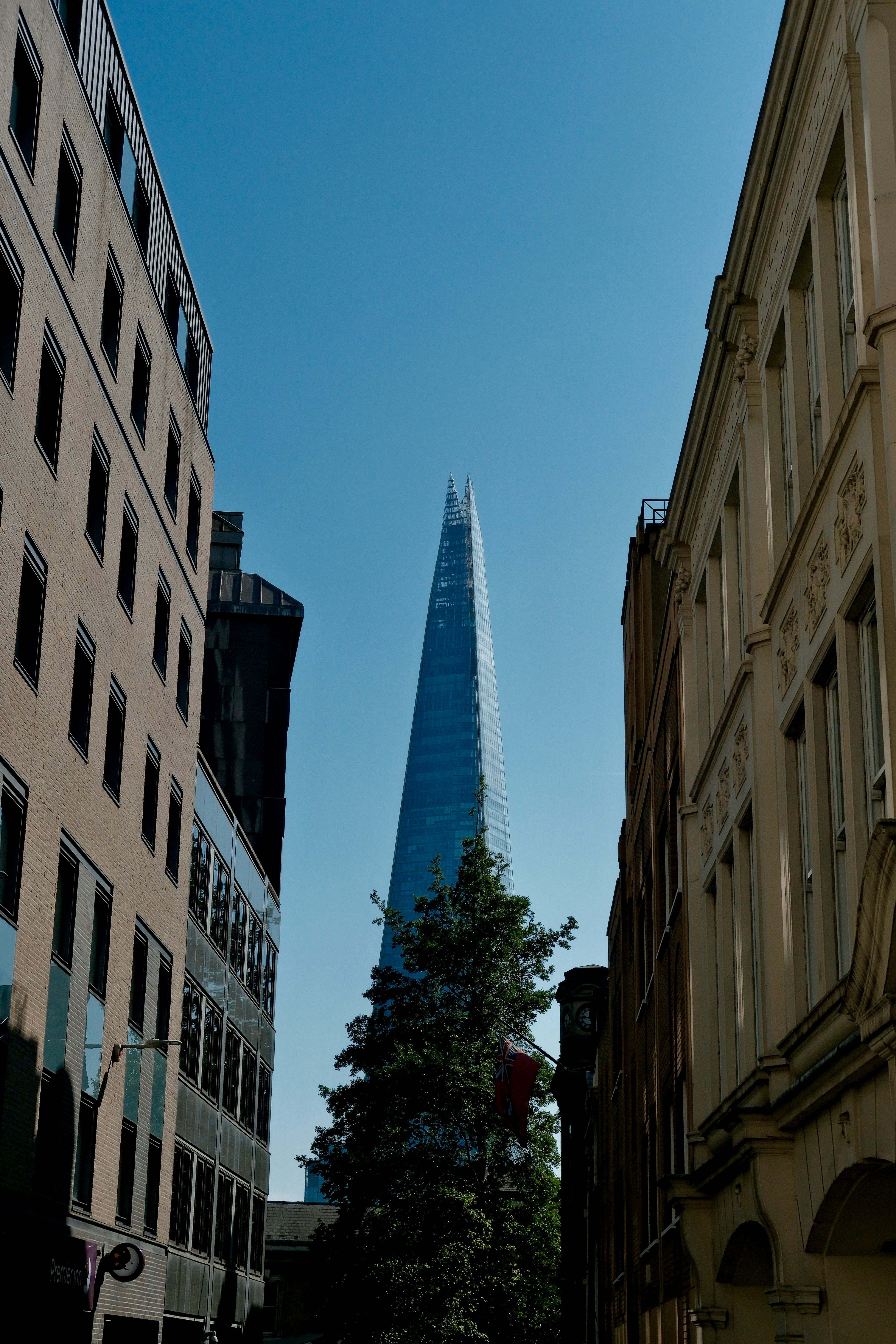 The shard towering between city buildings against a blue sky.